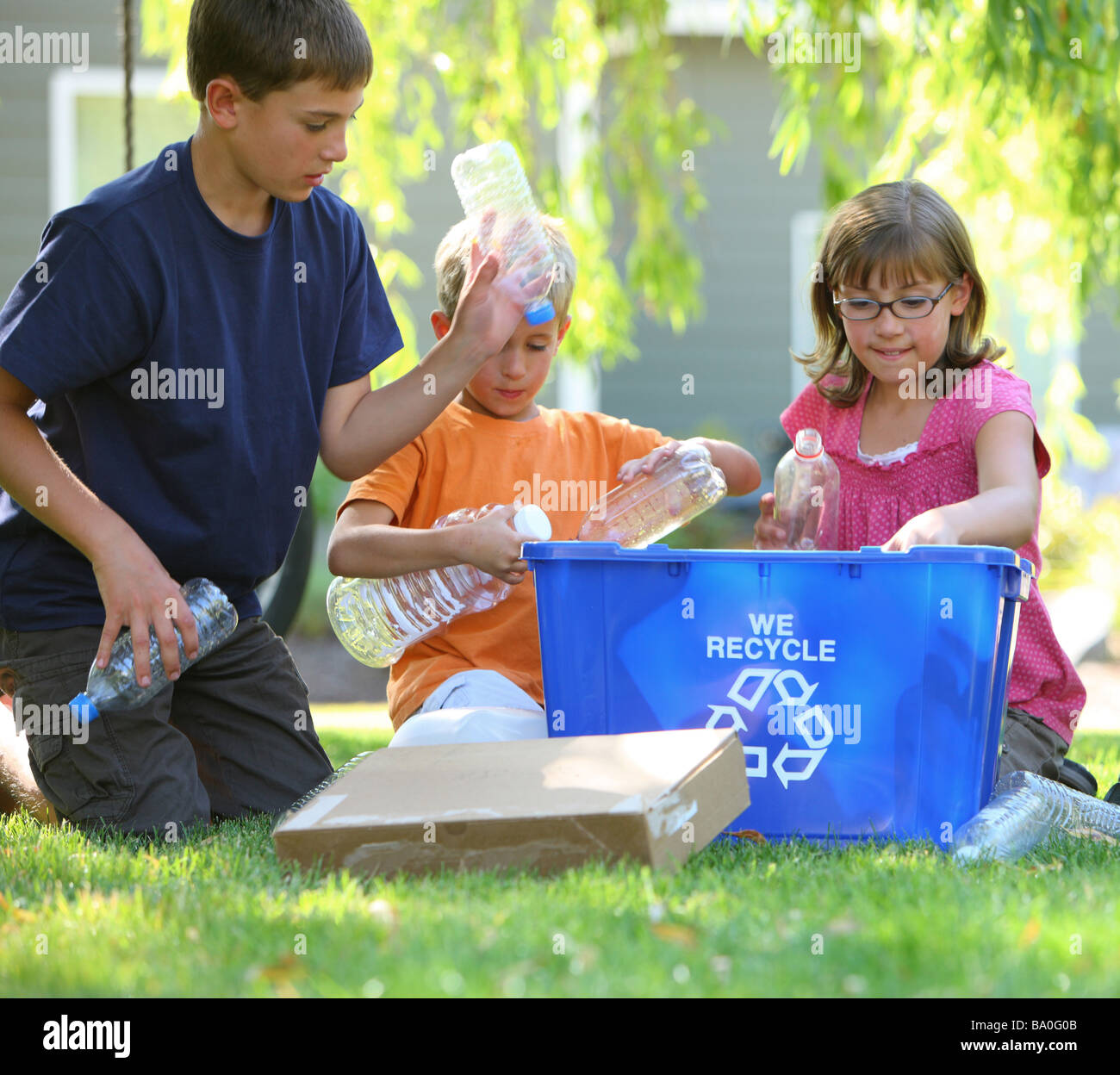 Group of children filling recycle bin Stock Photo - Alamy