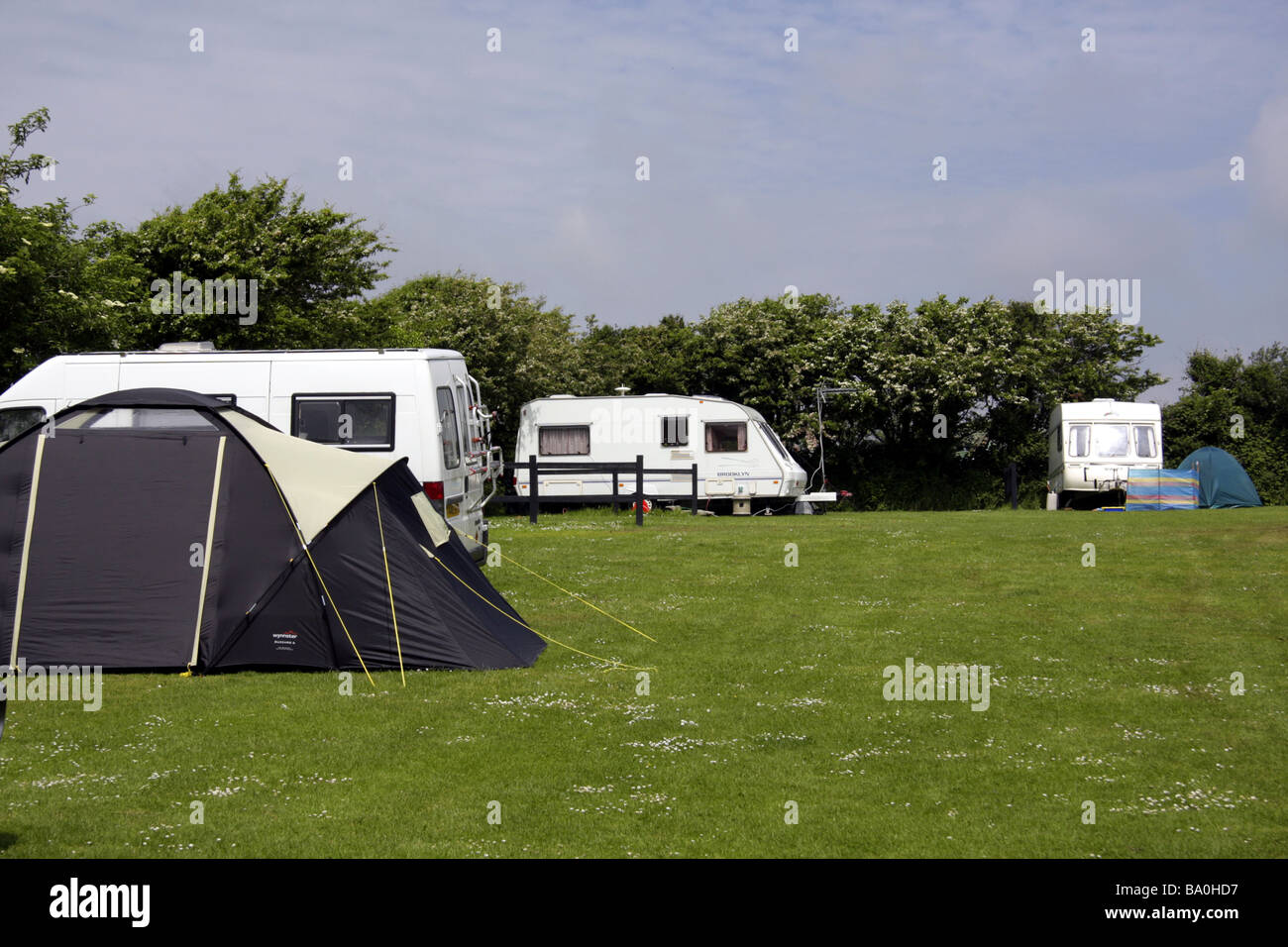 Caravans and a tent in a sunlit field at a holiday site near Port Eynon ...
