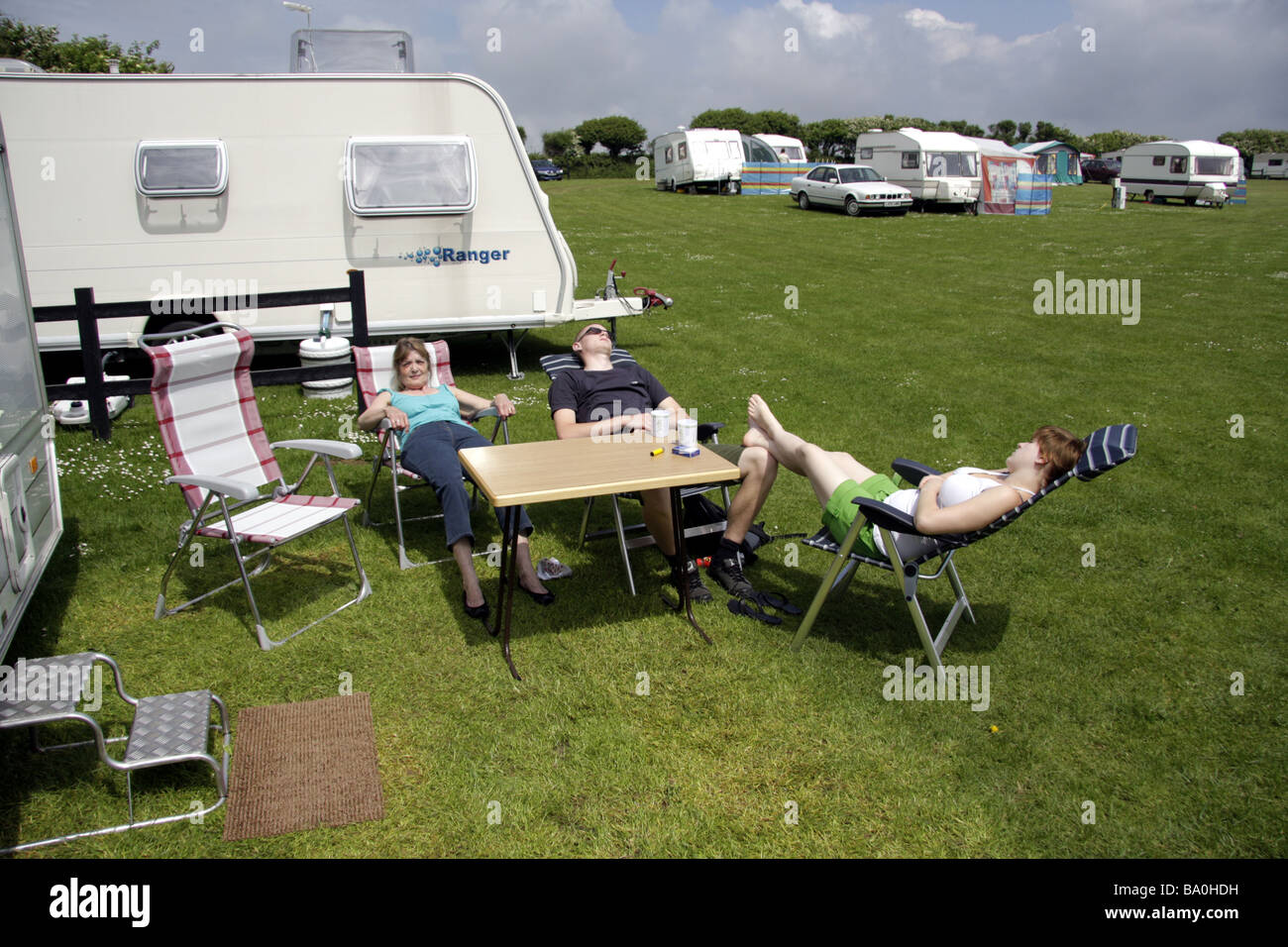 A family relaxing in the sun outside a caravan while on holiday in Port ...