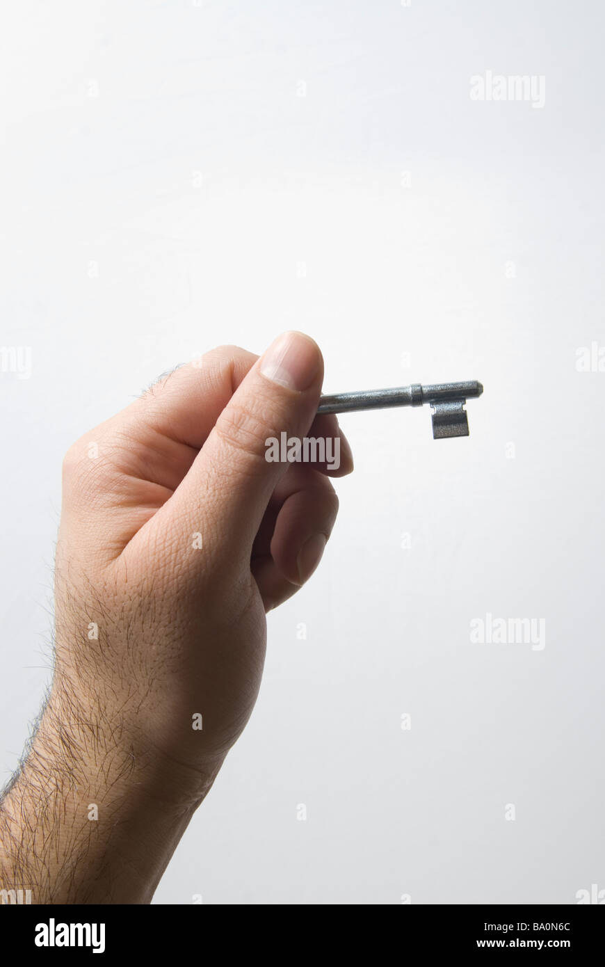 Hand holding a house key against a white background Stock Photo - Alamy