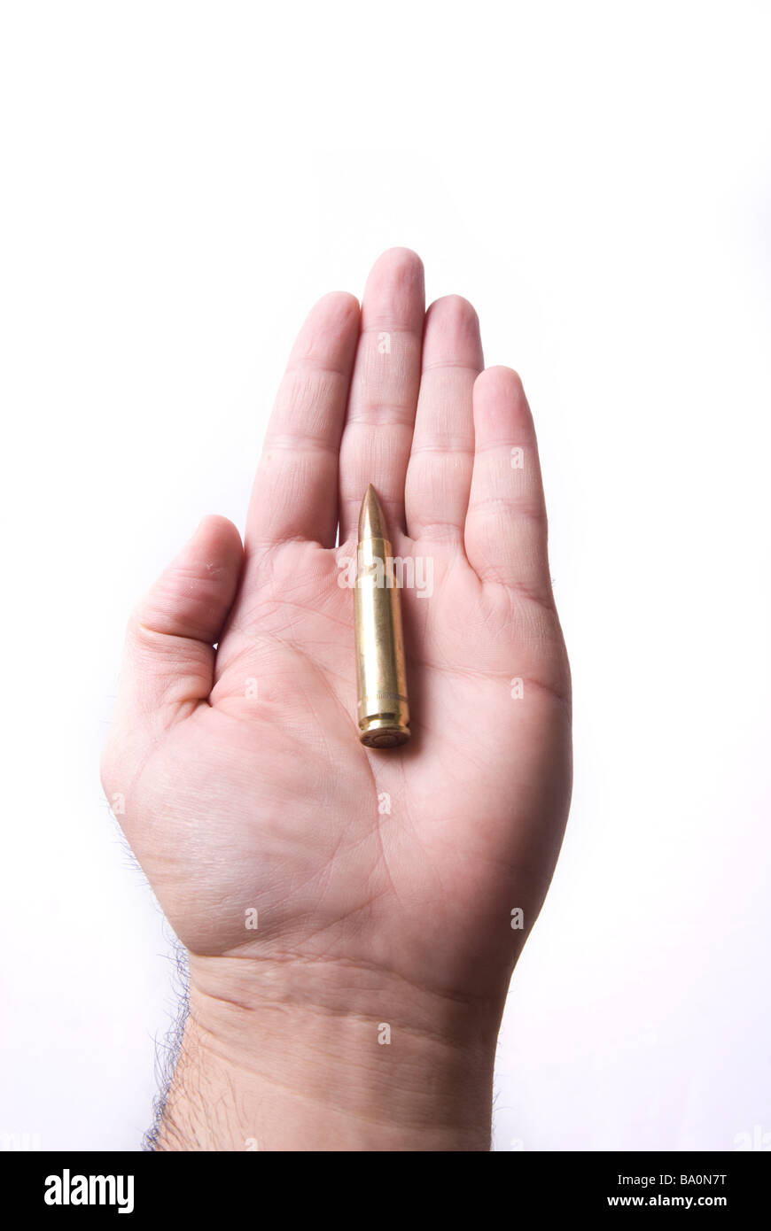 Hand holding a bullet against a white background Stock Photo - Alamy