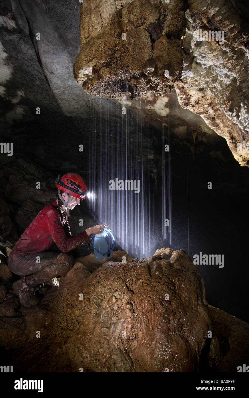 Young cave explorer filling her water container from a natural shower ...