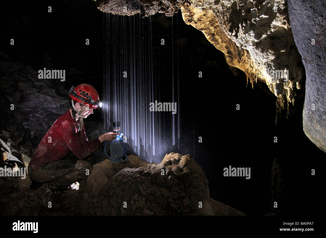 Young cave explorer filling her water container from a natural shower ...