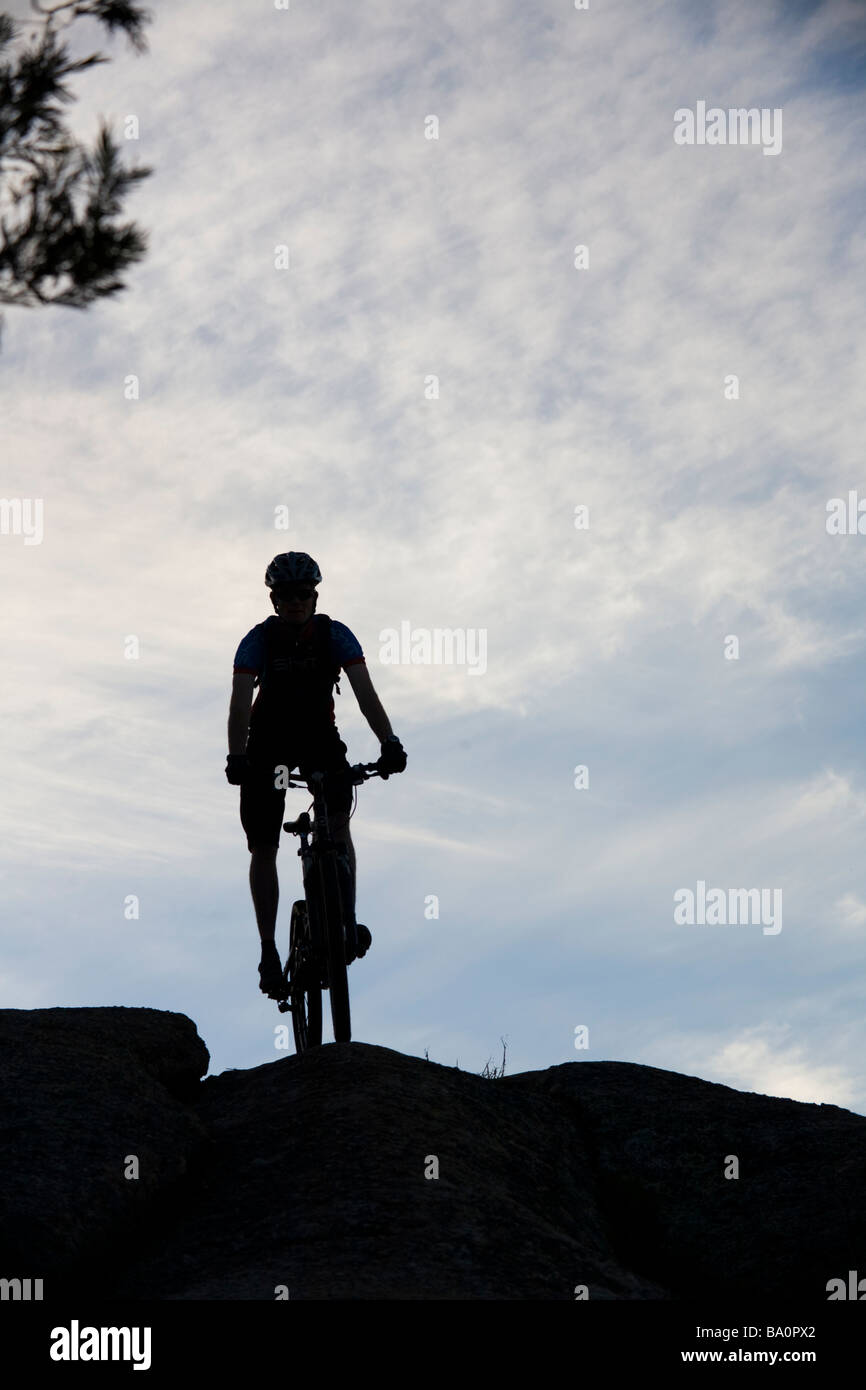 A Mountain biker rides over a large rock at dusk Stock Photo - Alamy