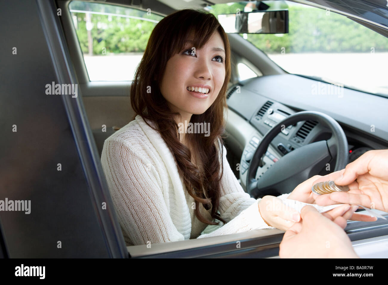 Young woman in car receiving change Stock Photo - Alamy