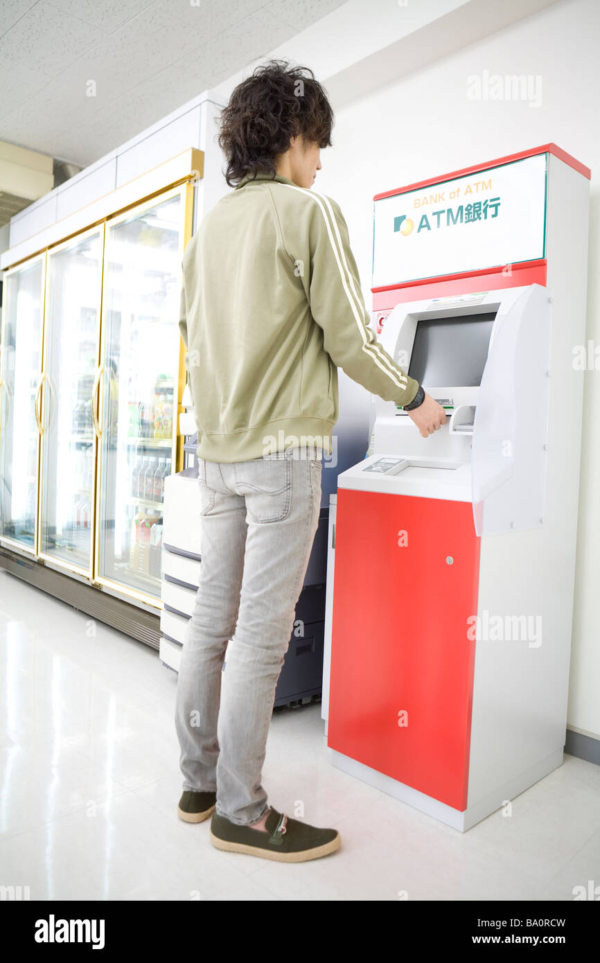 Customer at convenience store operating ATM Stock Photo - Alamy
