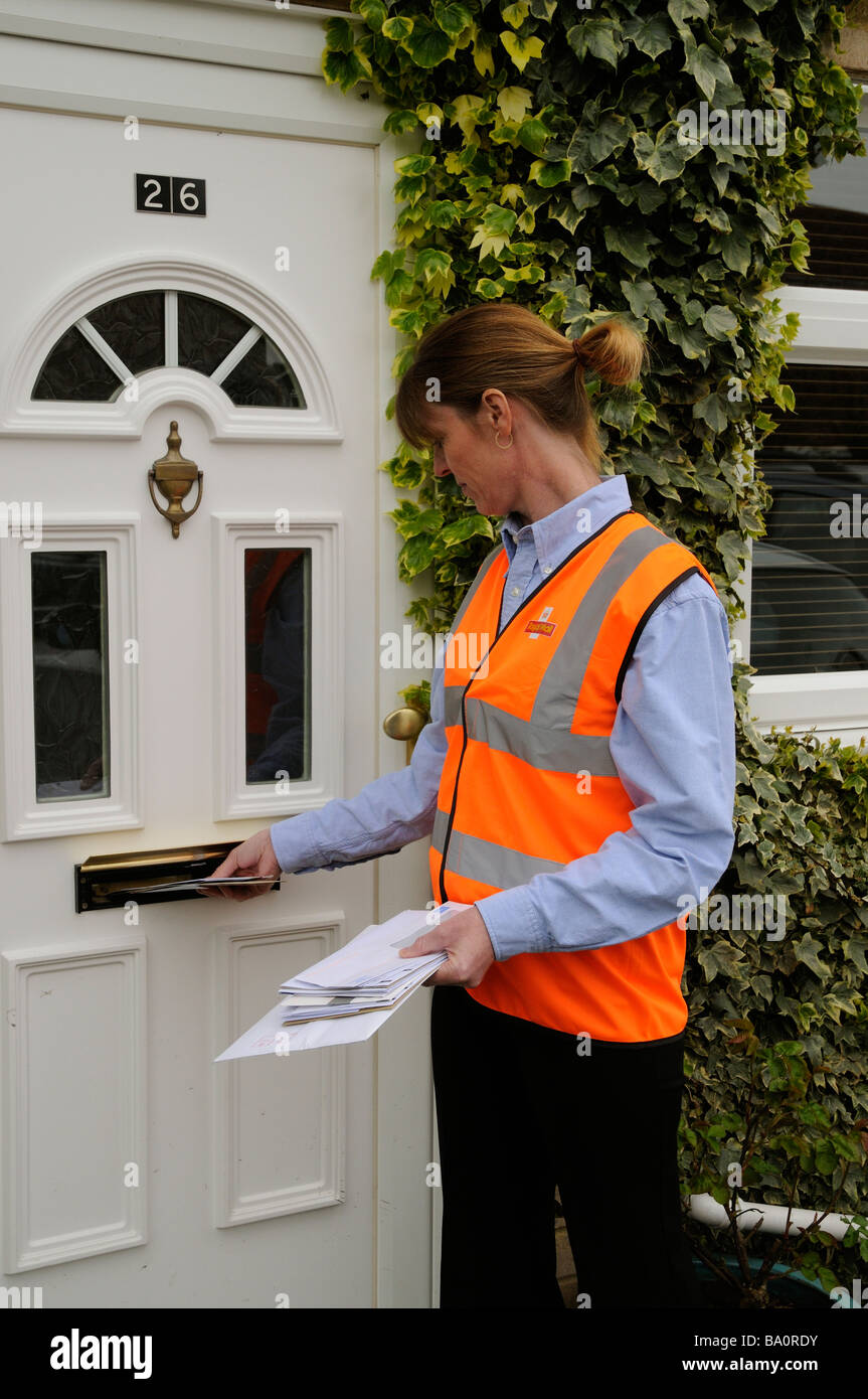 royal mail postwoman at the front door of a house delivering mail to a ...