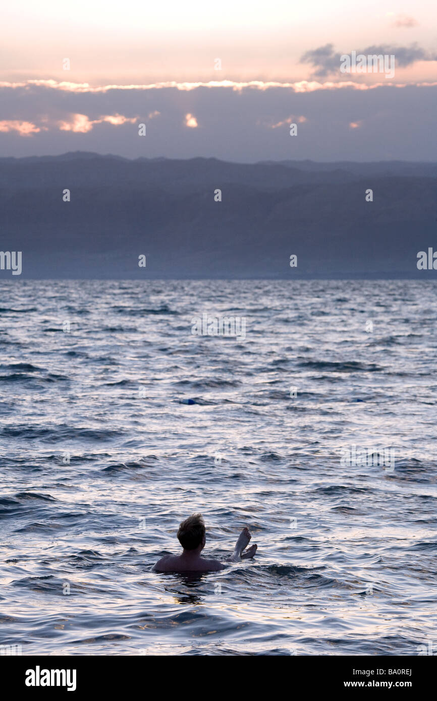 A lone swimmer floating in the Dead sea at sunset, looking towards ...