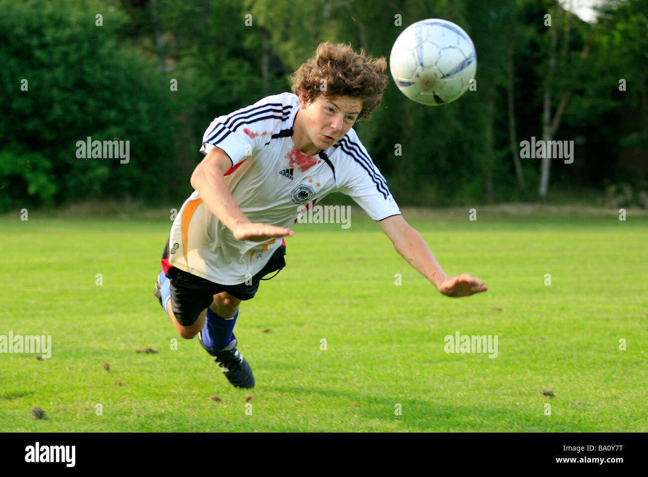 a teenage boy jumping to head a ball Stock Photo - Alamy