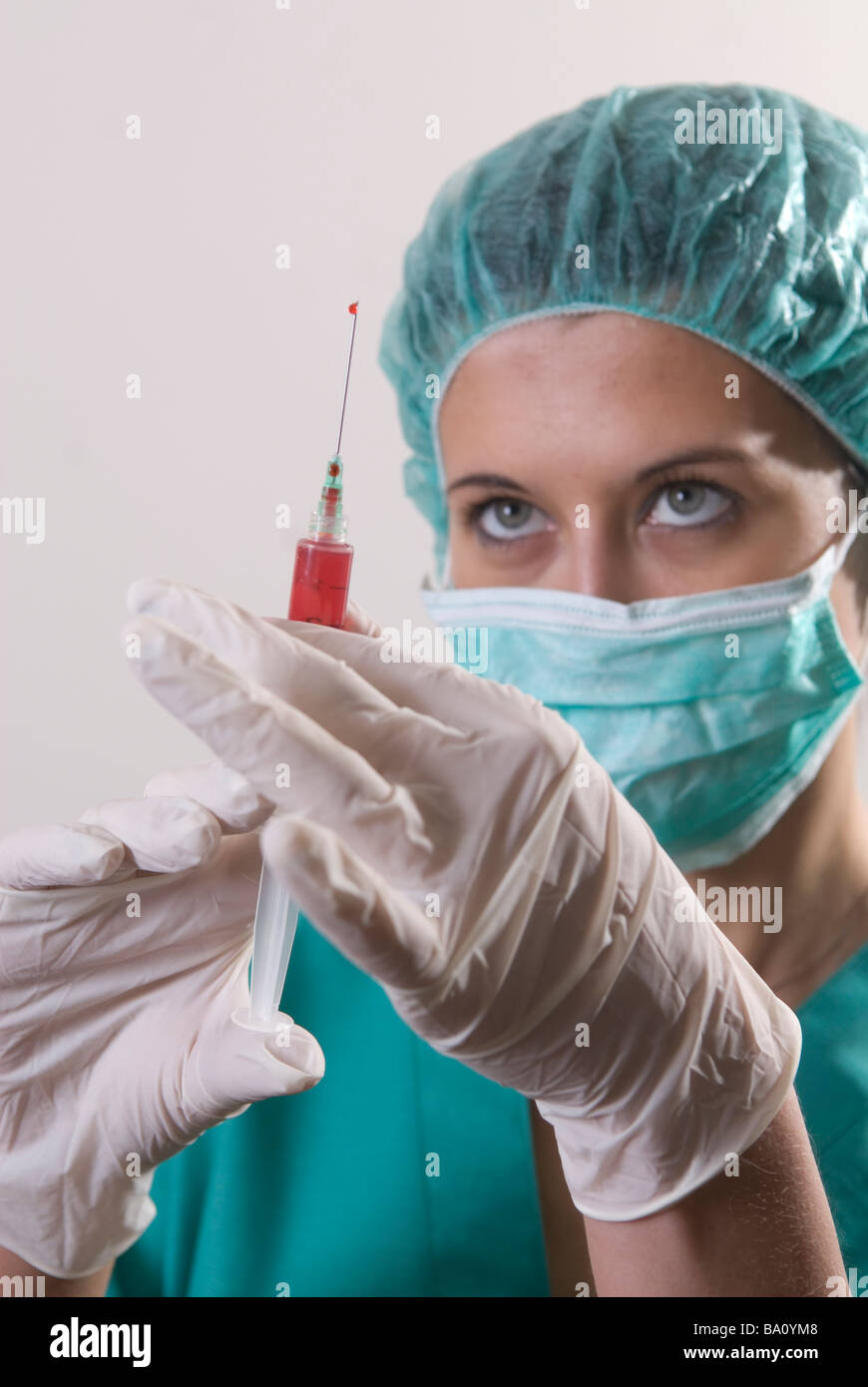 Young female nurse looking at injection filled with blood Stock Photo ...
