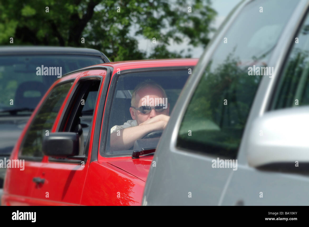 Car driver looking bored whilst stuck in a traffic jam in England Stock ...
