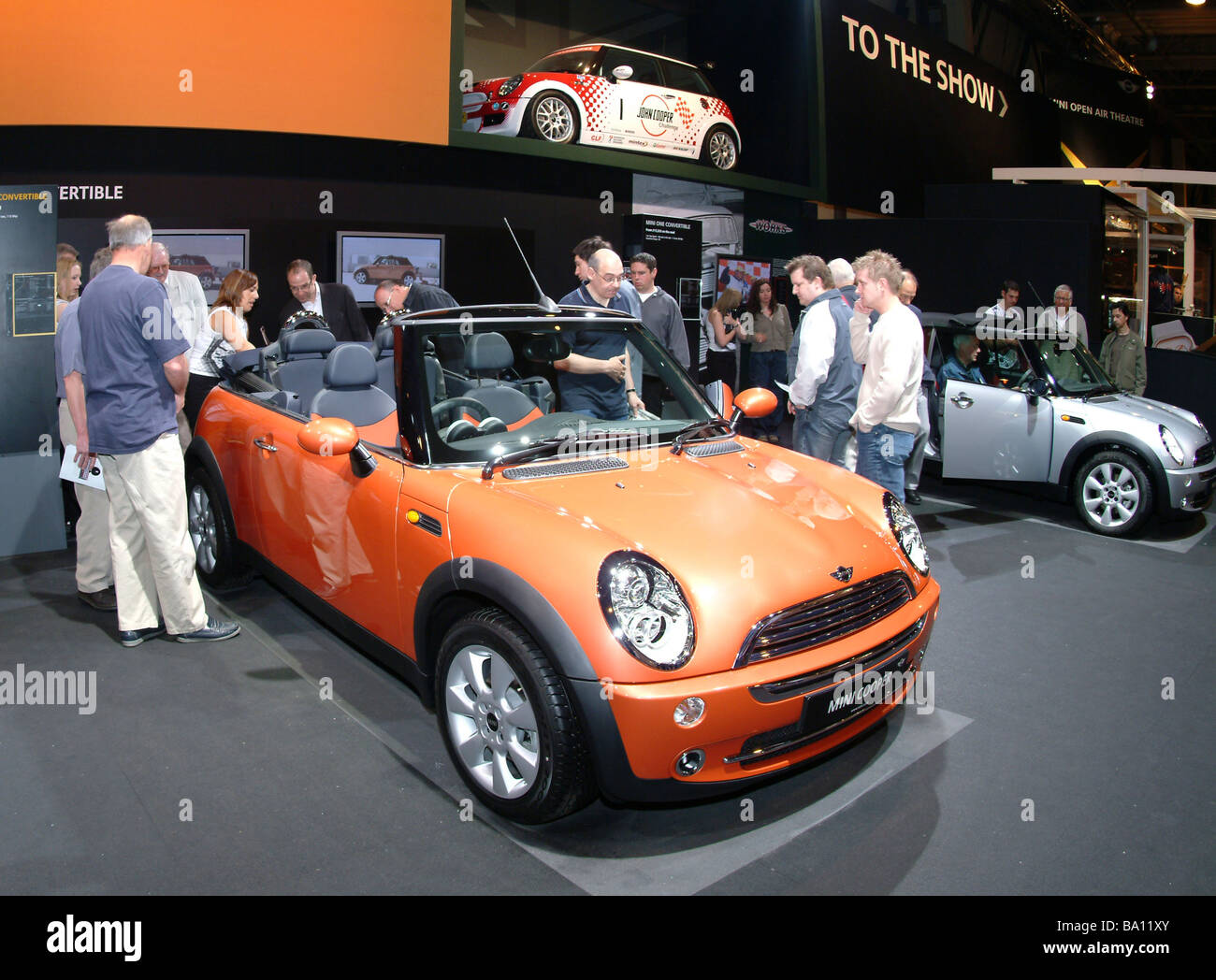 People looking at a new mini convertible at the 2004 British motorshow ...