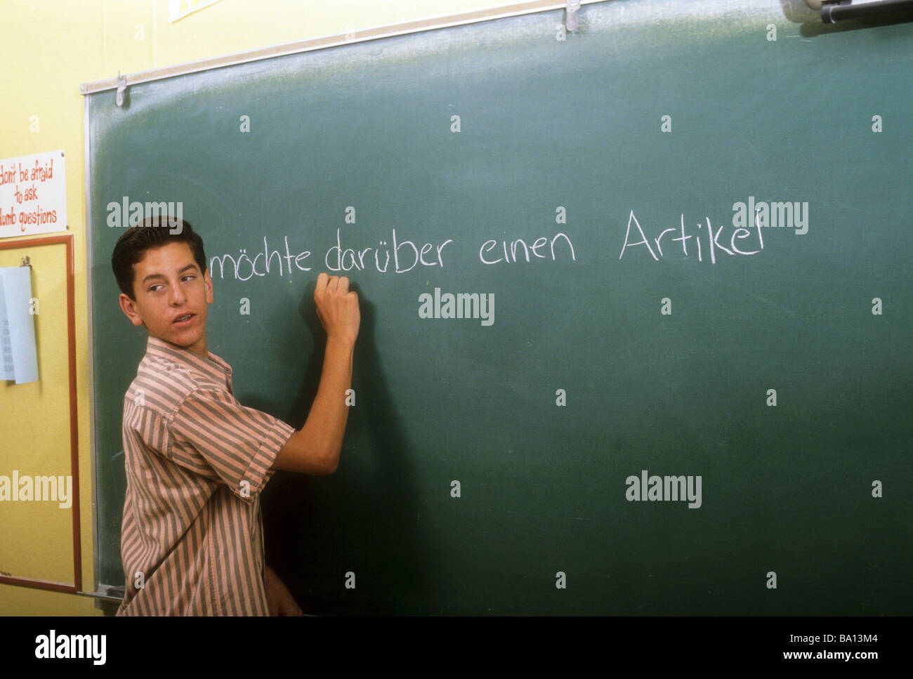 Hispanic teen boy write chalk board German class school learn practice ...