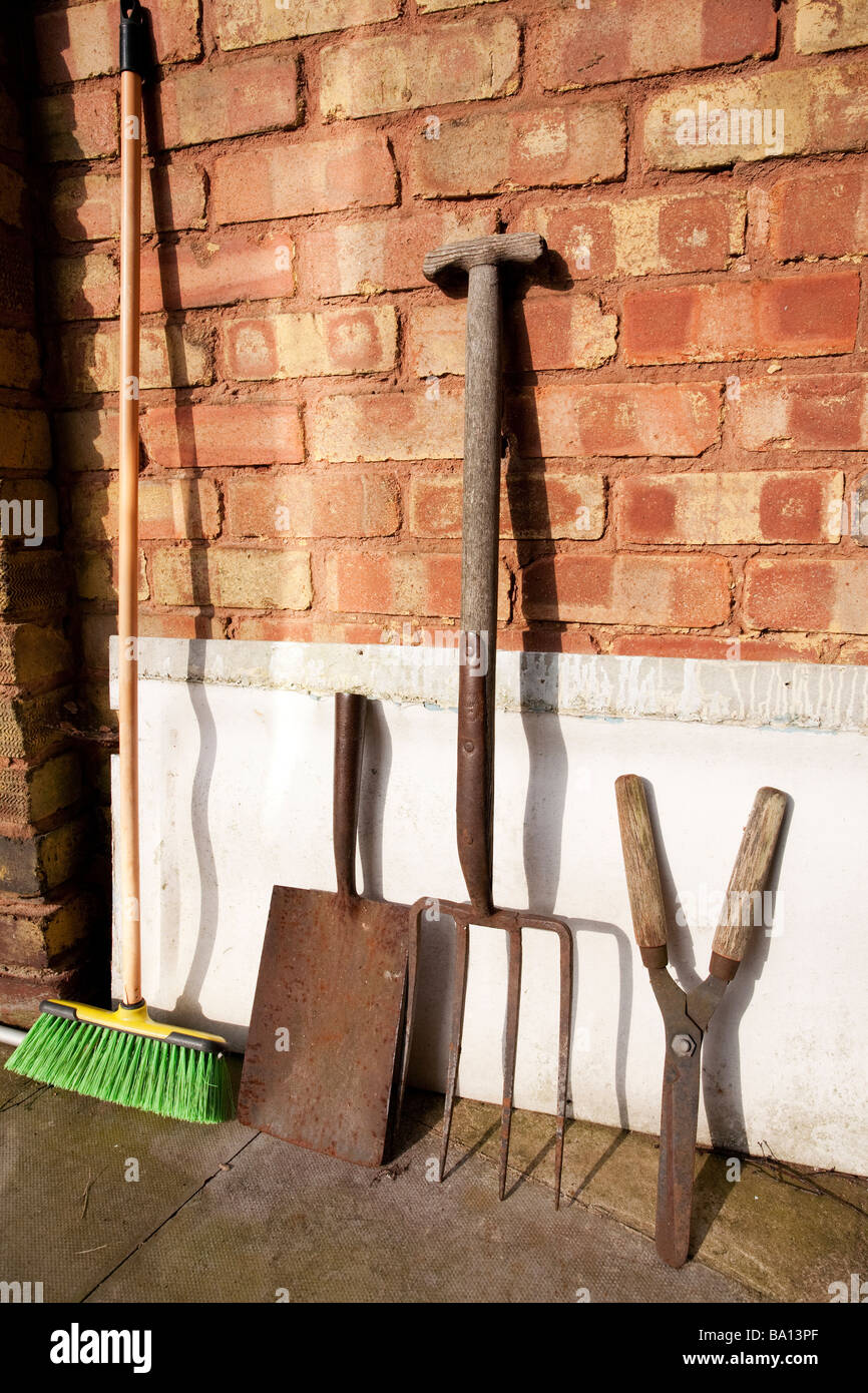 garden tools leaning against a brick wall Stock Photo - Alamy