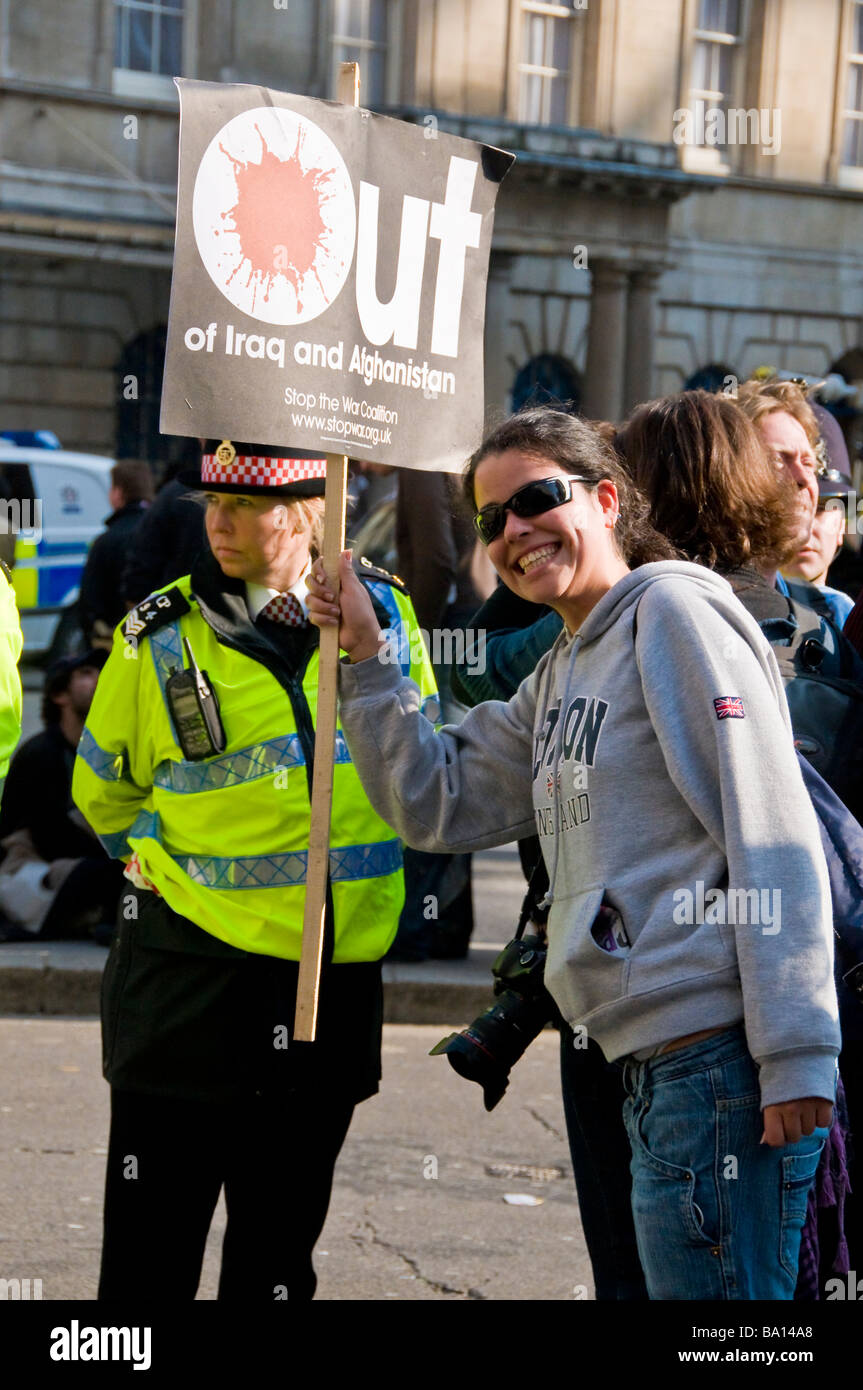 A young girl protester posing with an anti-war banner and a policewoman ...