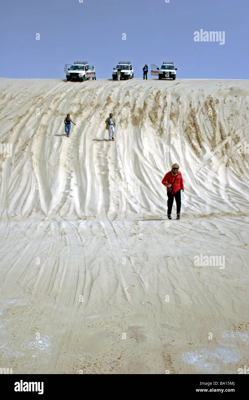 Three People Are Coming Down A Sand hill In Formation While Three Jeeps ...