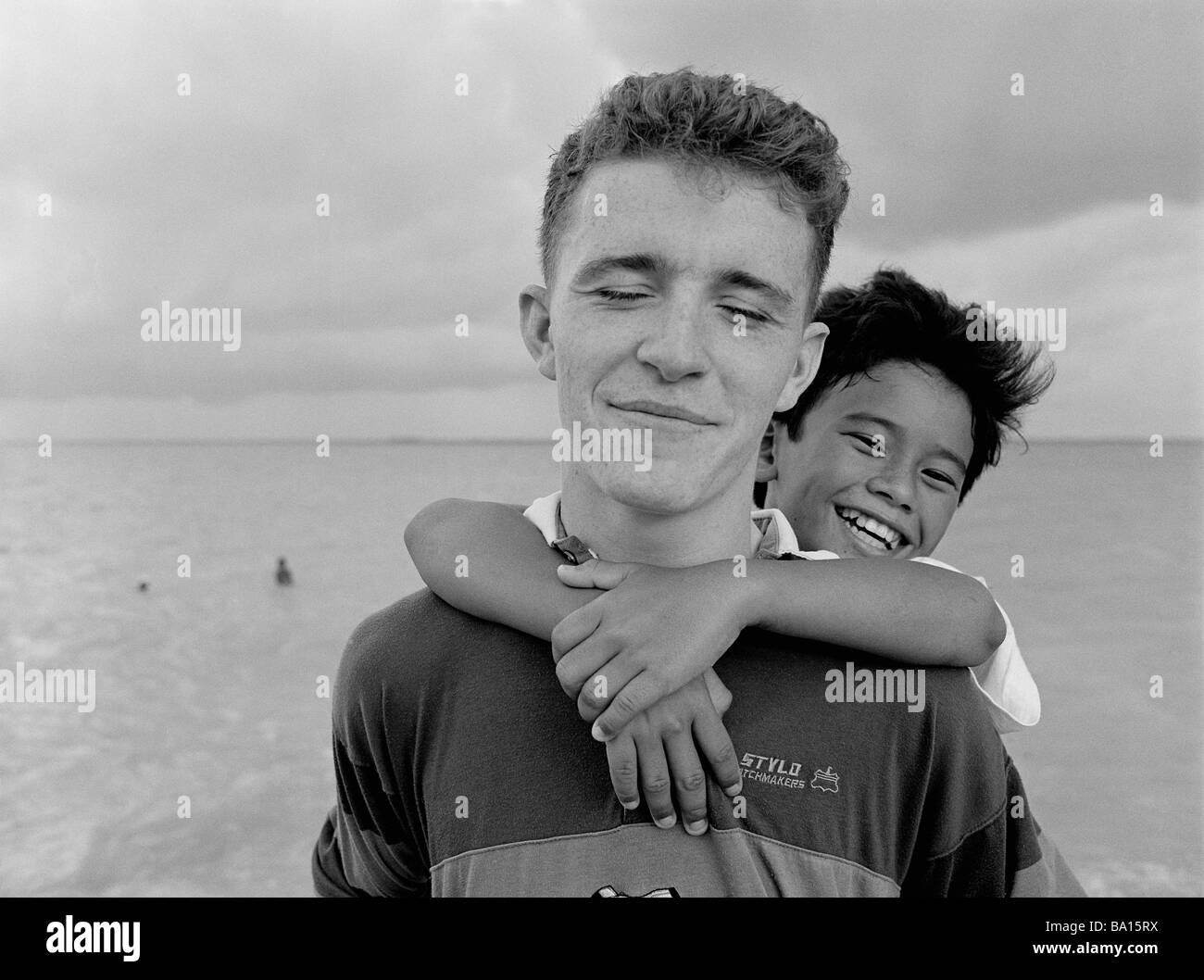 Western teenager playing with young boy on beach of Caribbean corozal ...