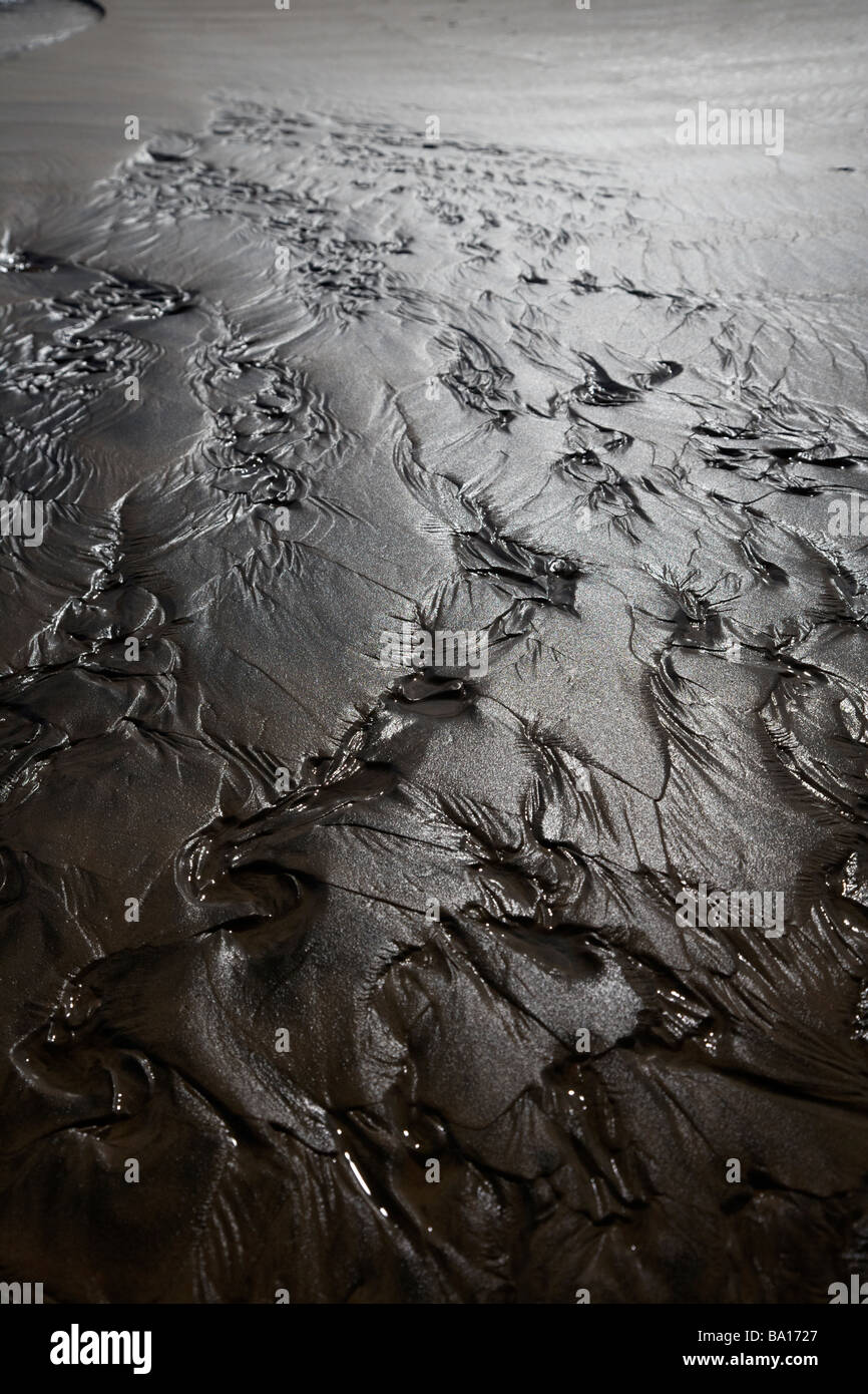 marks on a sandy beach made by water flowing down to the sea with ...