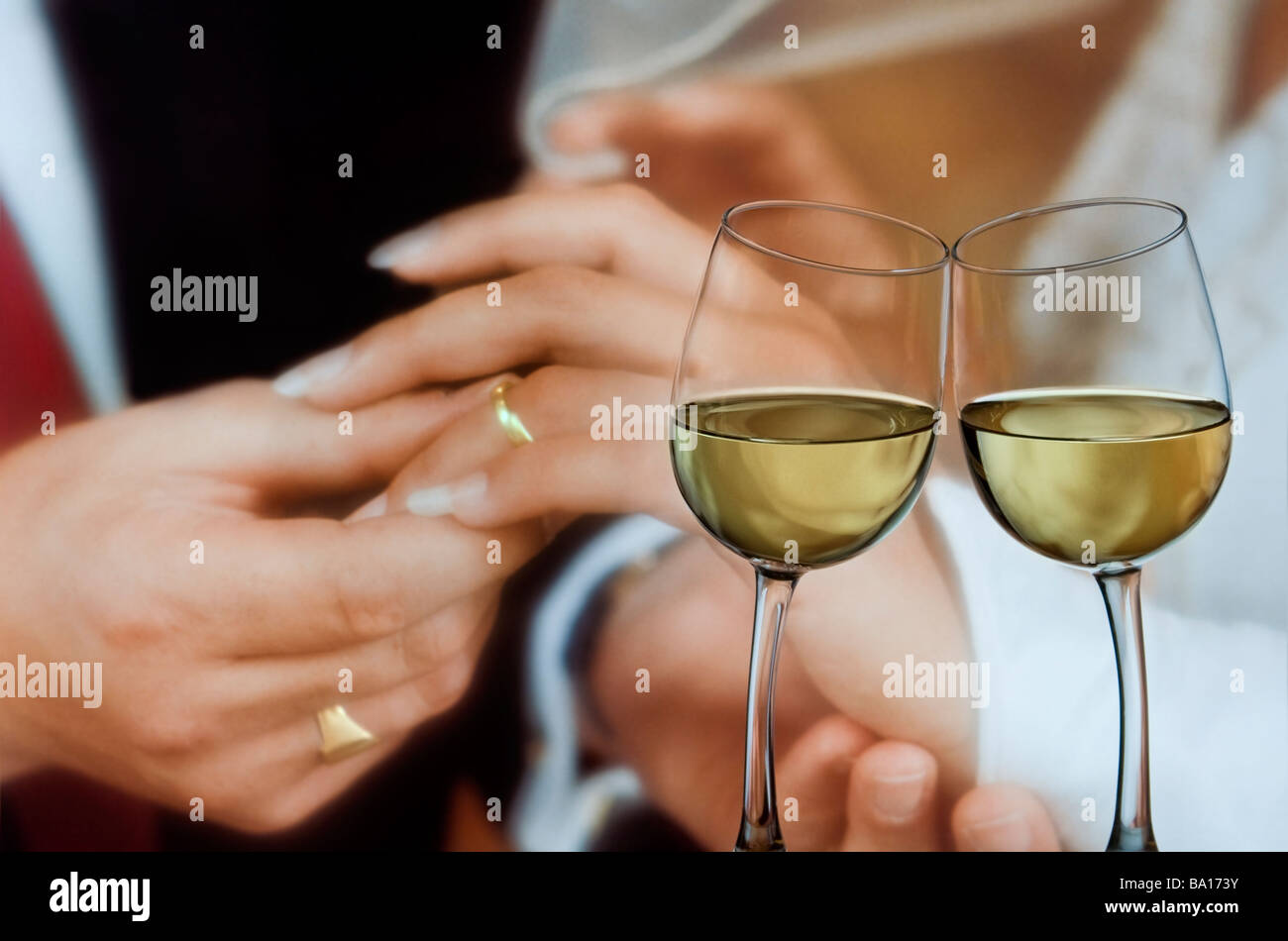 Two wine glasses lean towards each other with Bride and Groom behind ...