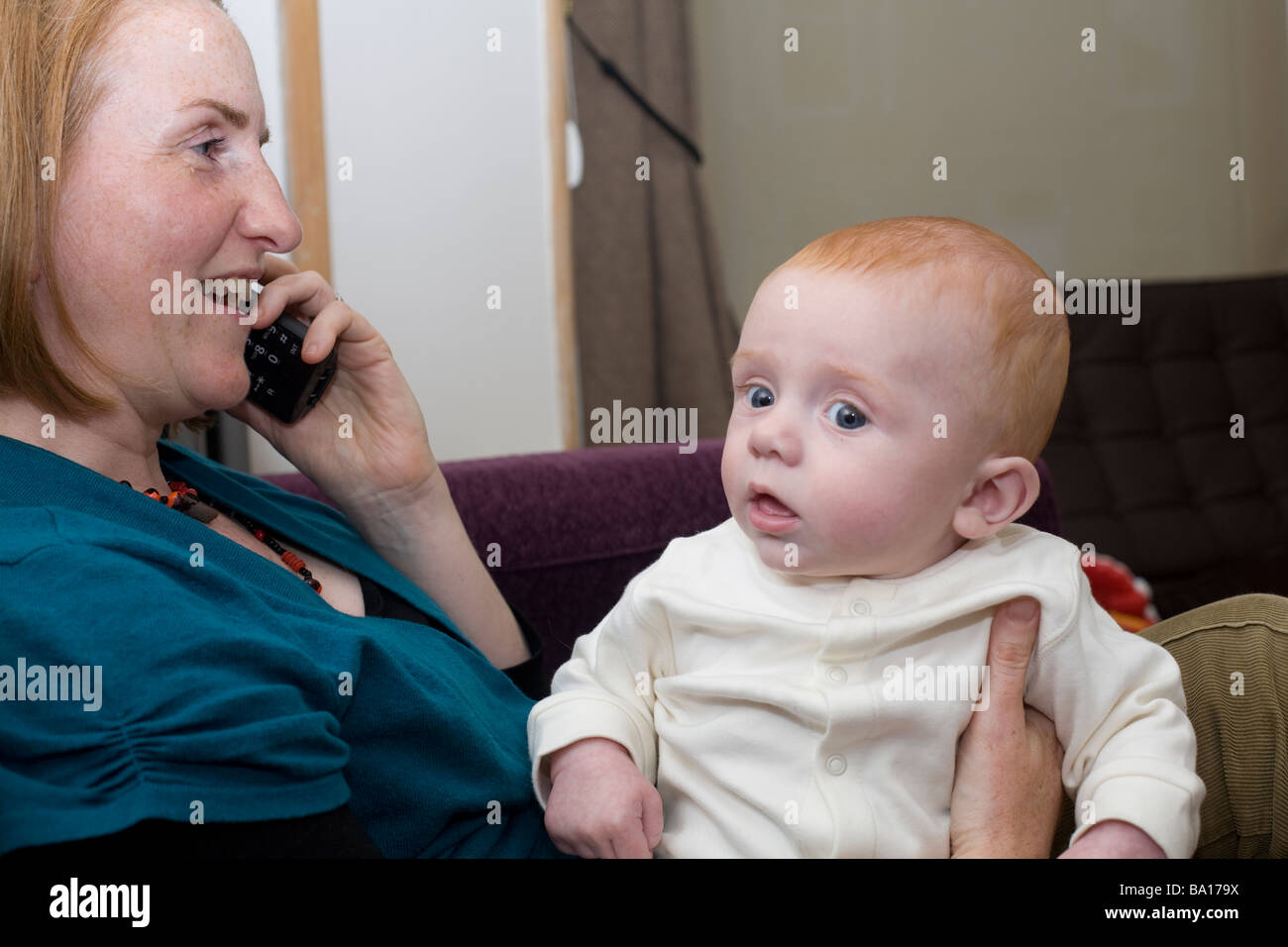 Baby boy with busy mother Stock Photo - Alamy