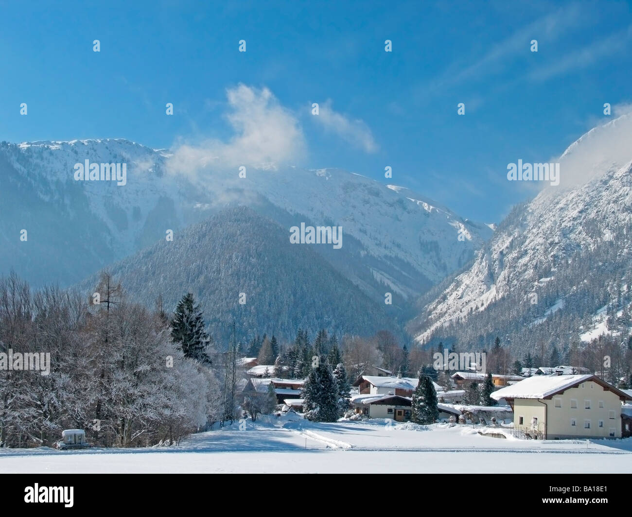 Pretty village at the footage of Tirol mountains in blue ski winter day ...