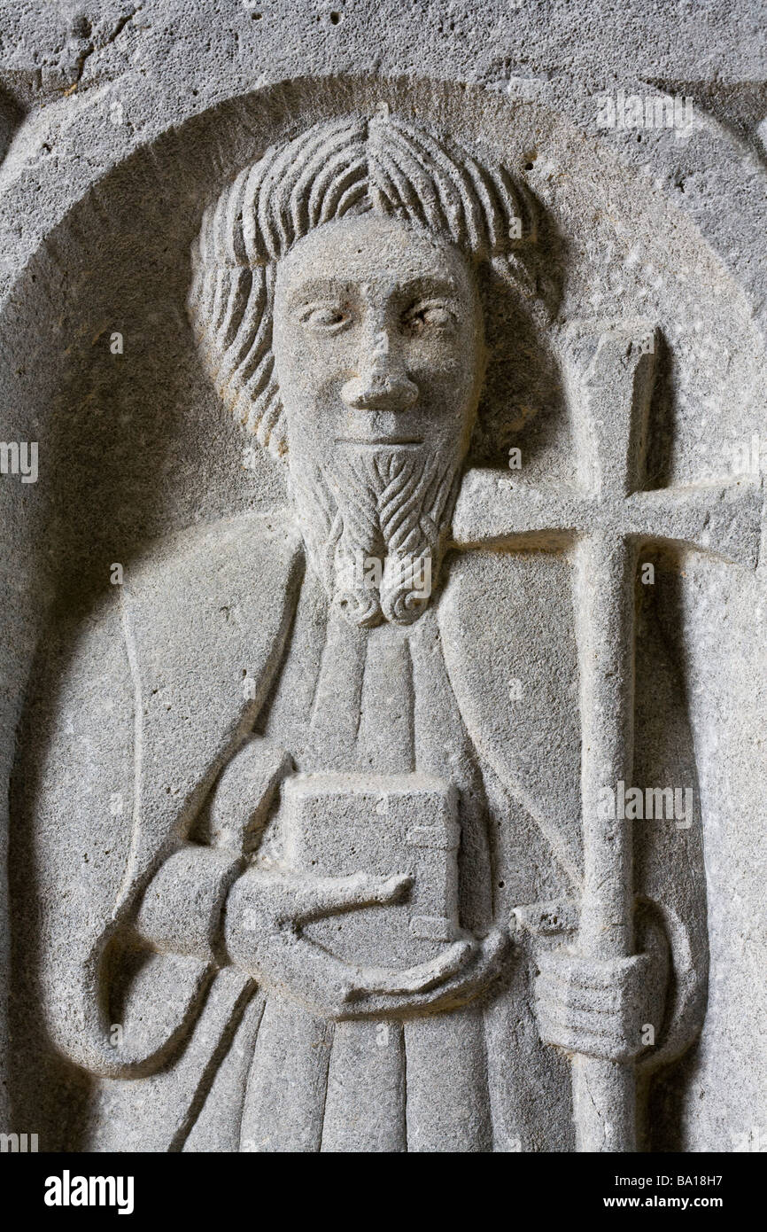 Saint with a cross and a bible. A carved relief on the side of a coffin ...