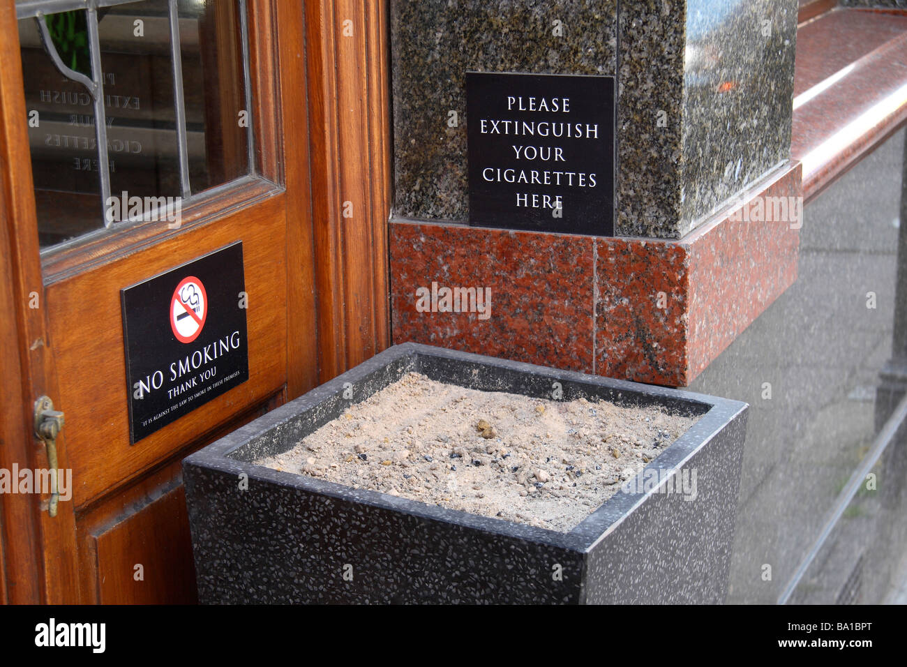 'Please extinguish your cigarettes here' sign. An external smoking area ...