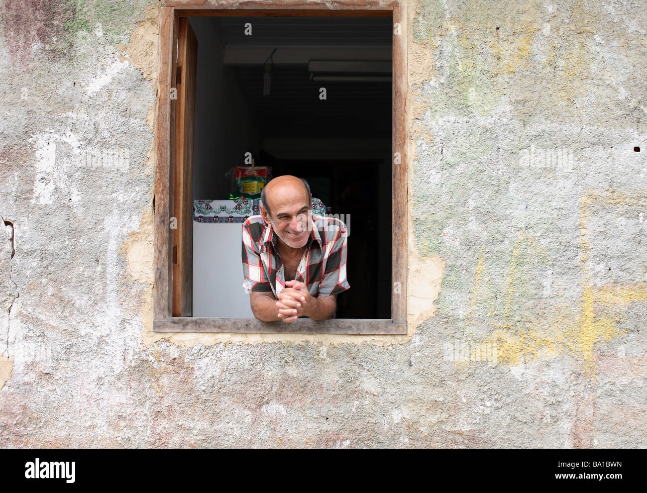 Local village man leaning out of window Stock Photo - Alamy