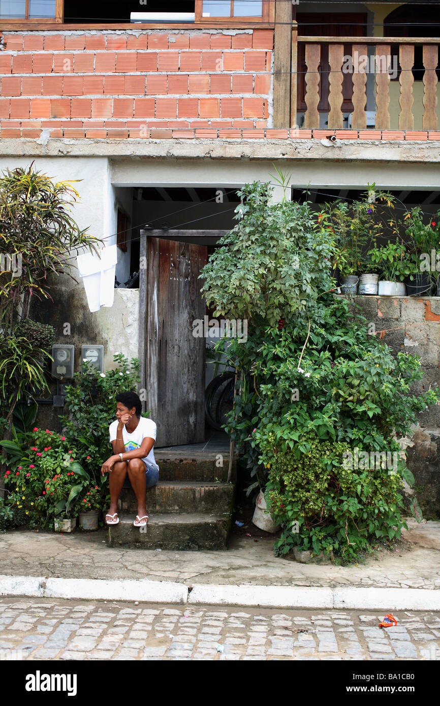 Local resident sitting on steps of house in Paraty Stock Photo - Alamy