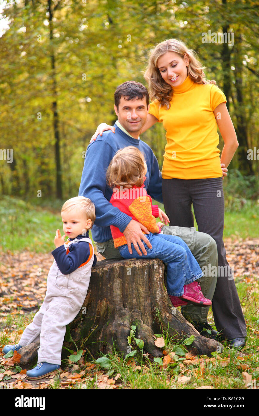 Parents with children sit on stub in forest in autumn Stock Photo - Alamy