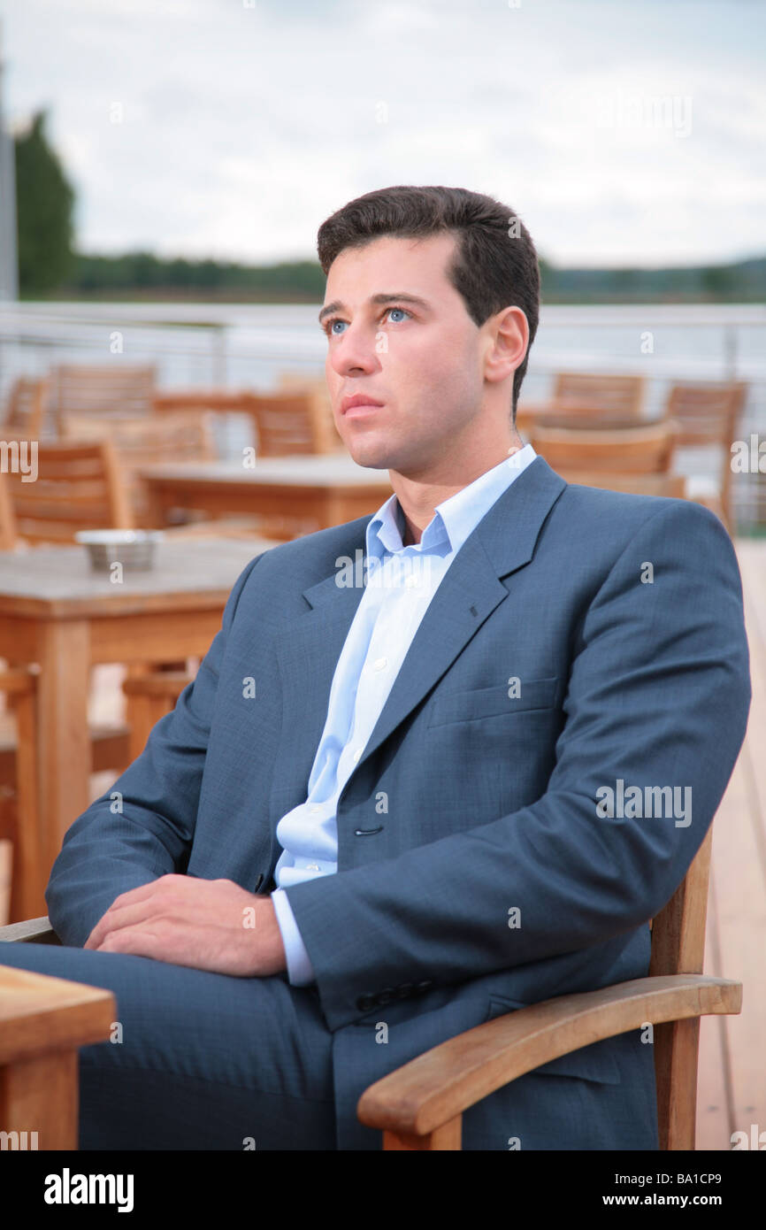 Portrait of man, who sits behind table in cafe near water Stock Photo ...