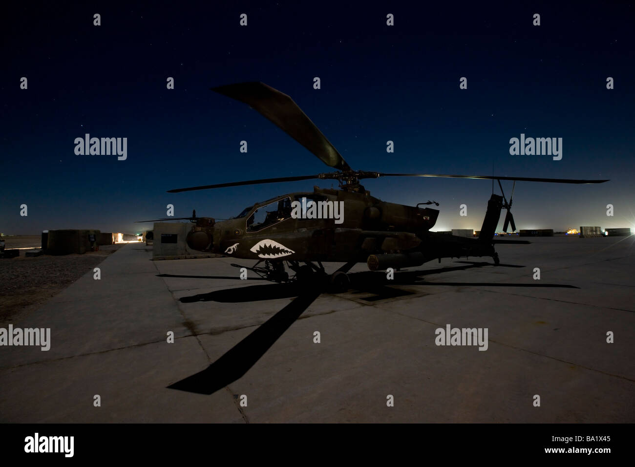 An AH-64 Apache waits on the flight line at night at Camp Speicher ...