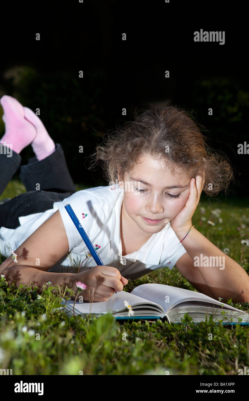 Child laying in the grass doing homework Stock Photo - Alamy