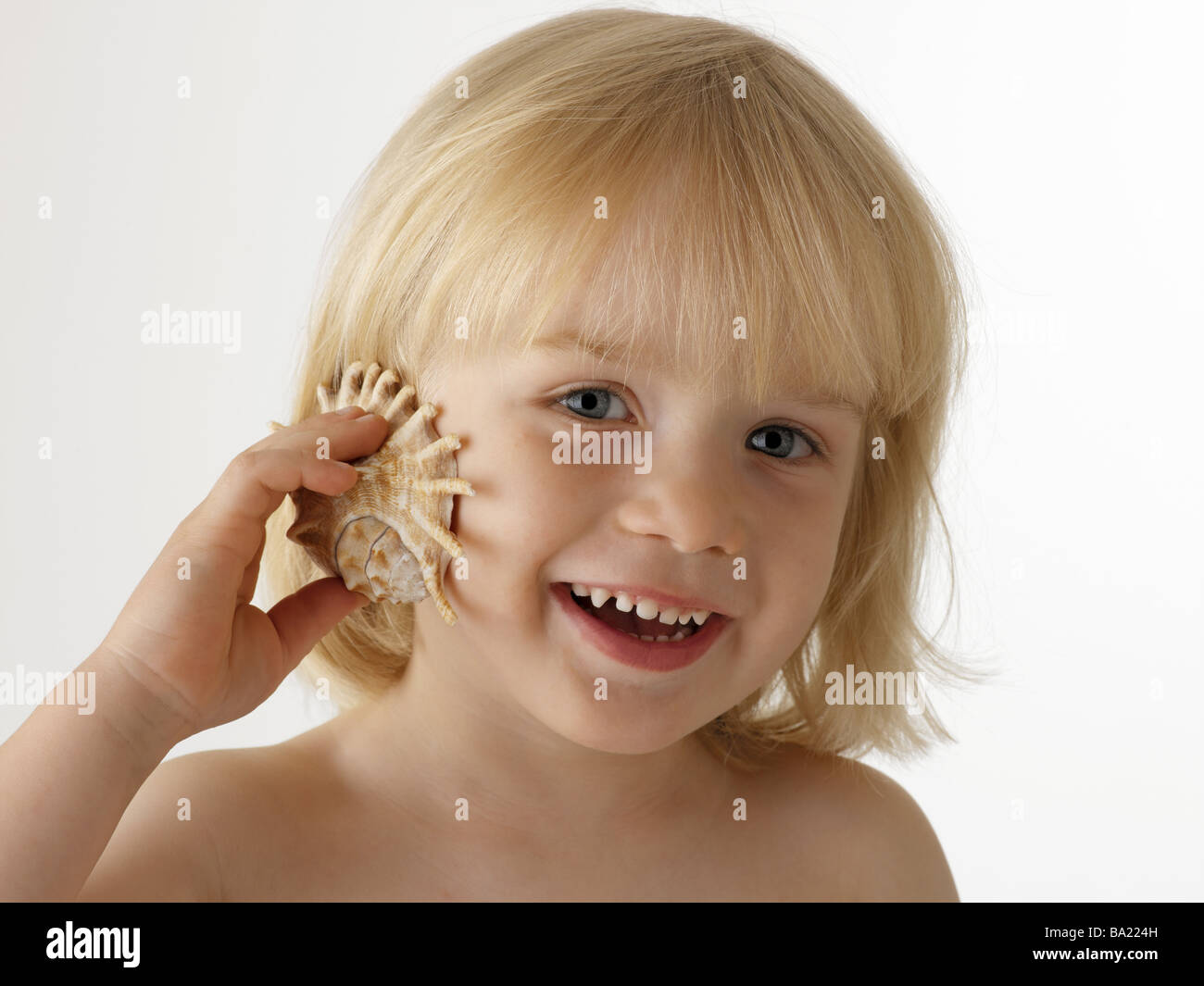 Child blond upper bodies freely ear mussel listens smiles portrait ...