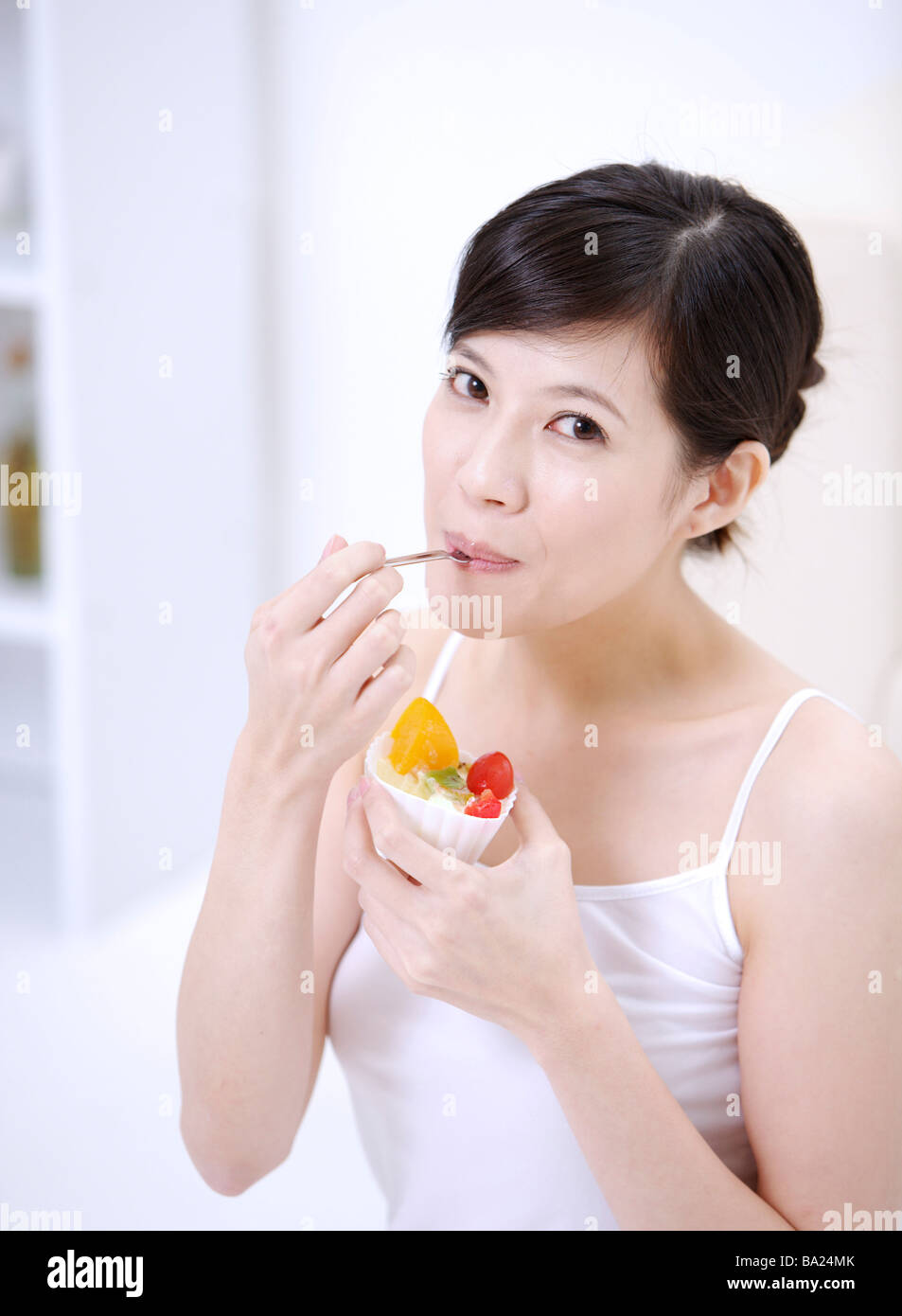 Young woman eating bowl of dessert looking at camera smiling close up ...