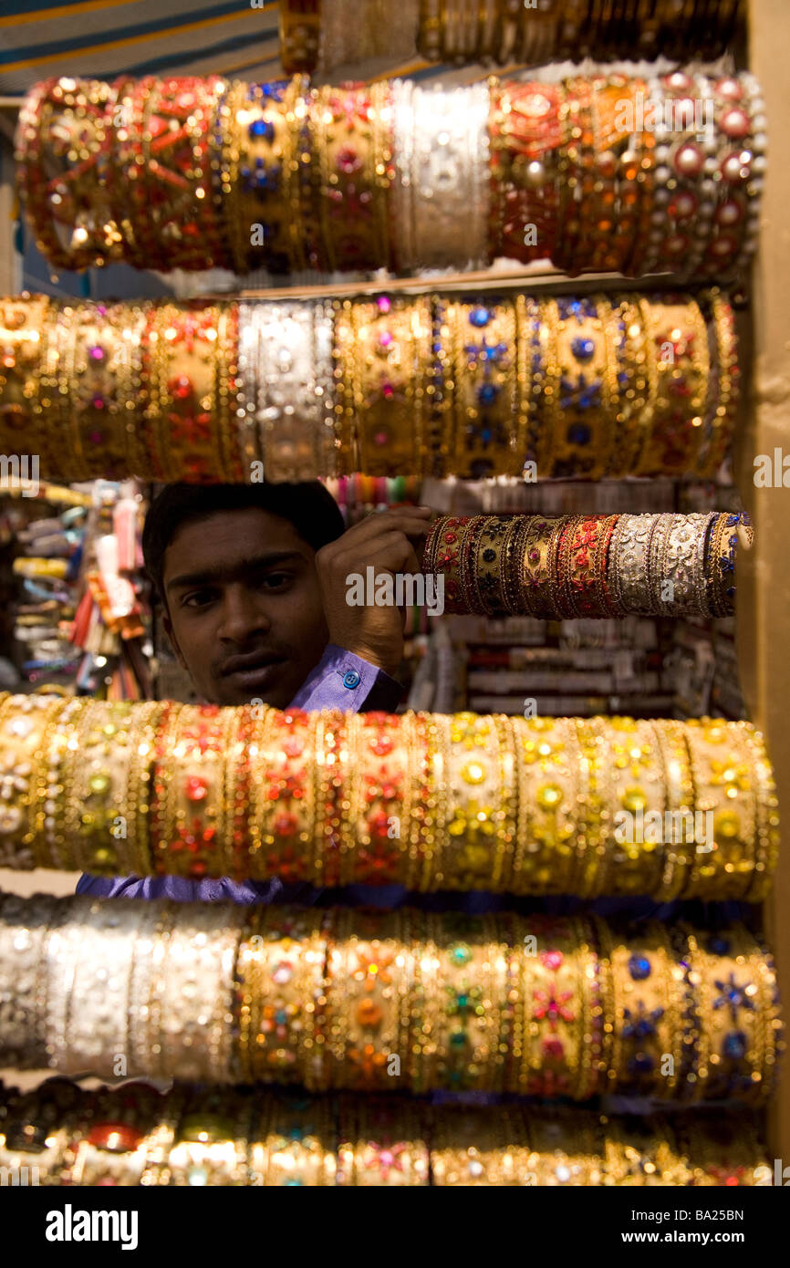 A young man holds up a set of bangles at a shop in Commercial Street in ...