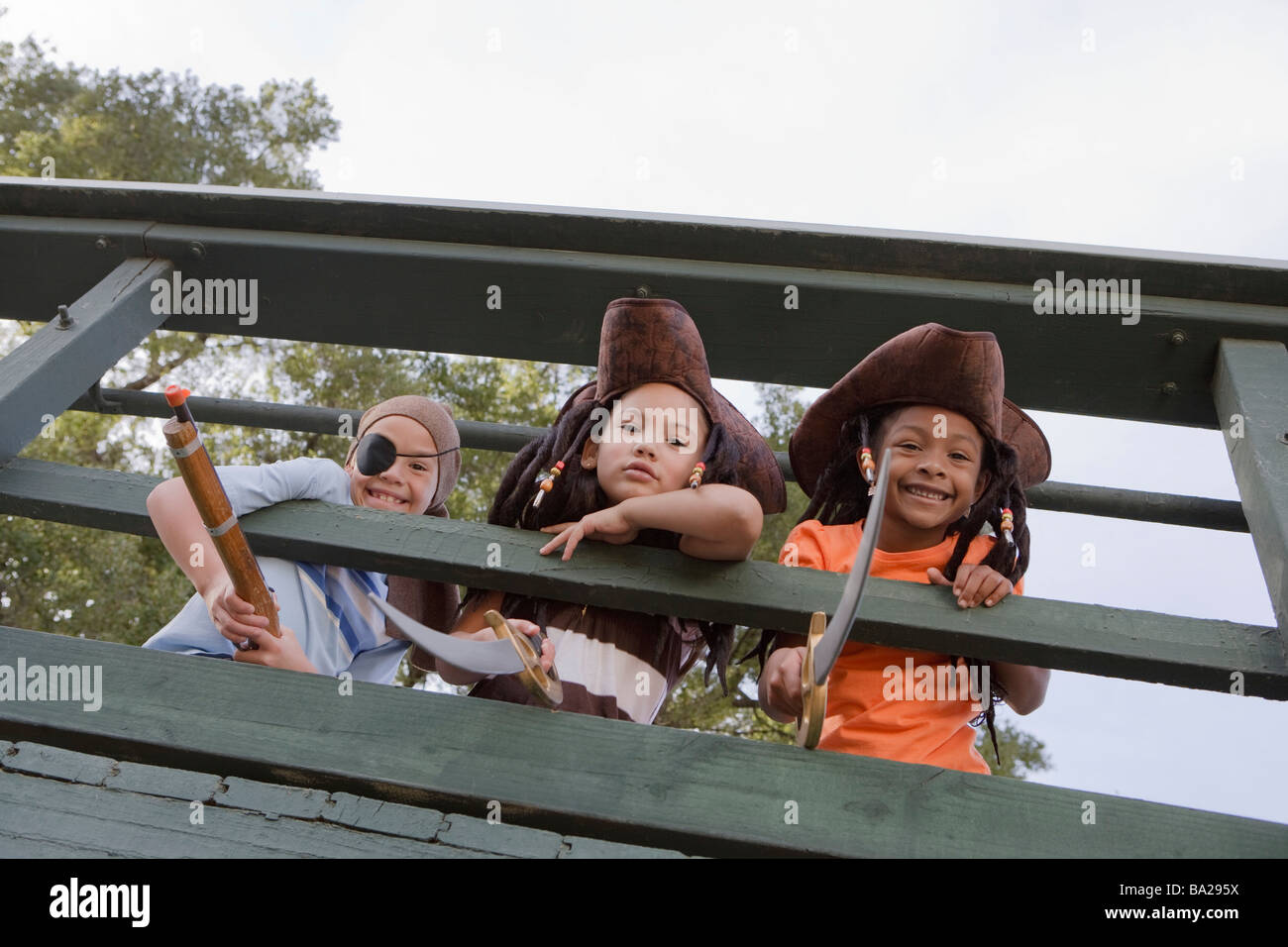 Three boys (7-9) wearing costumes looking down from bridge Stock Photo ...
