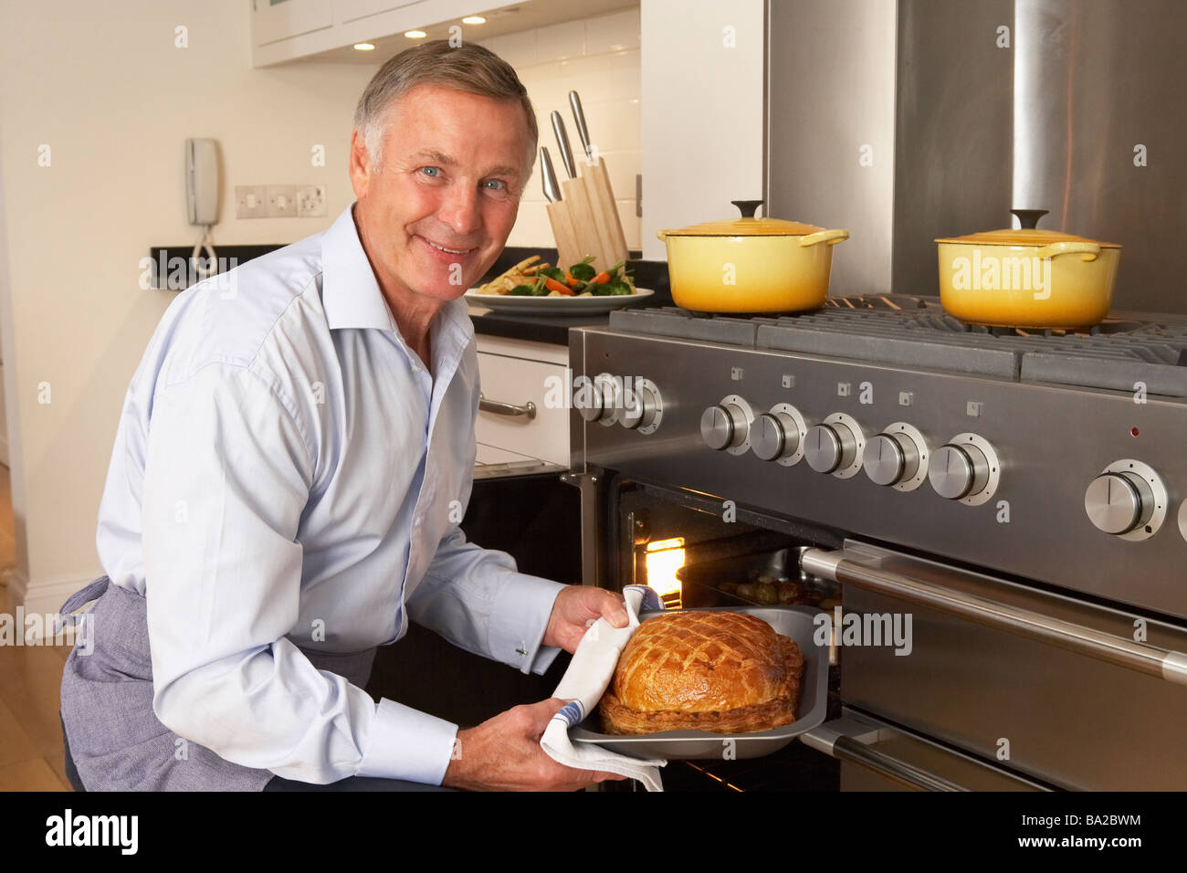 Man Taking Food Out Of The Oven Stock Photo - Alamy