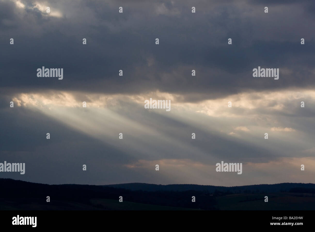 Sunbeam through grey clouds over field Stock Photo - Alamy