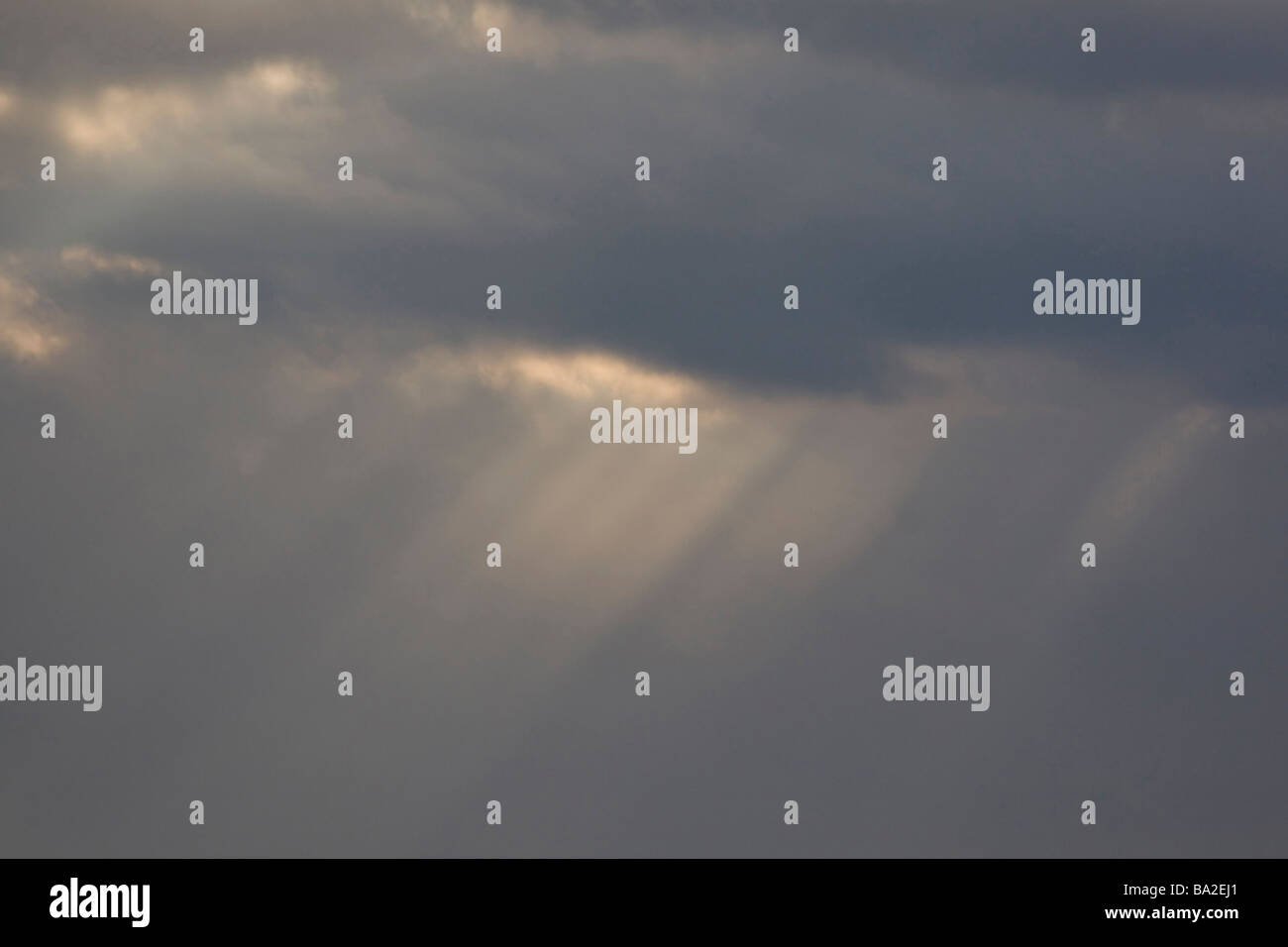 Sunbeam through grey clouds over field Stock Photo - Alamy