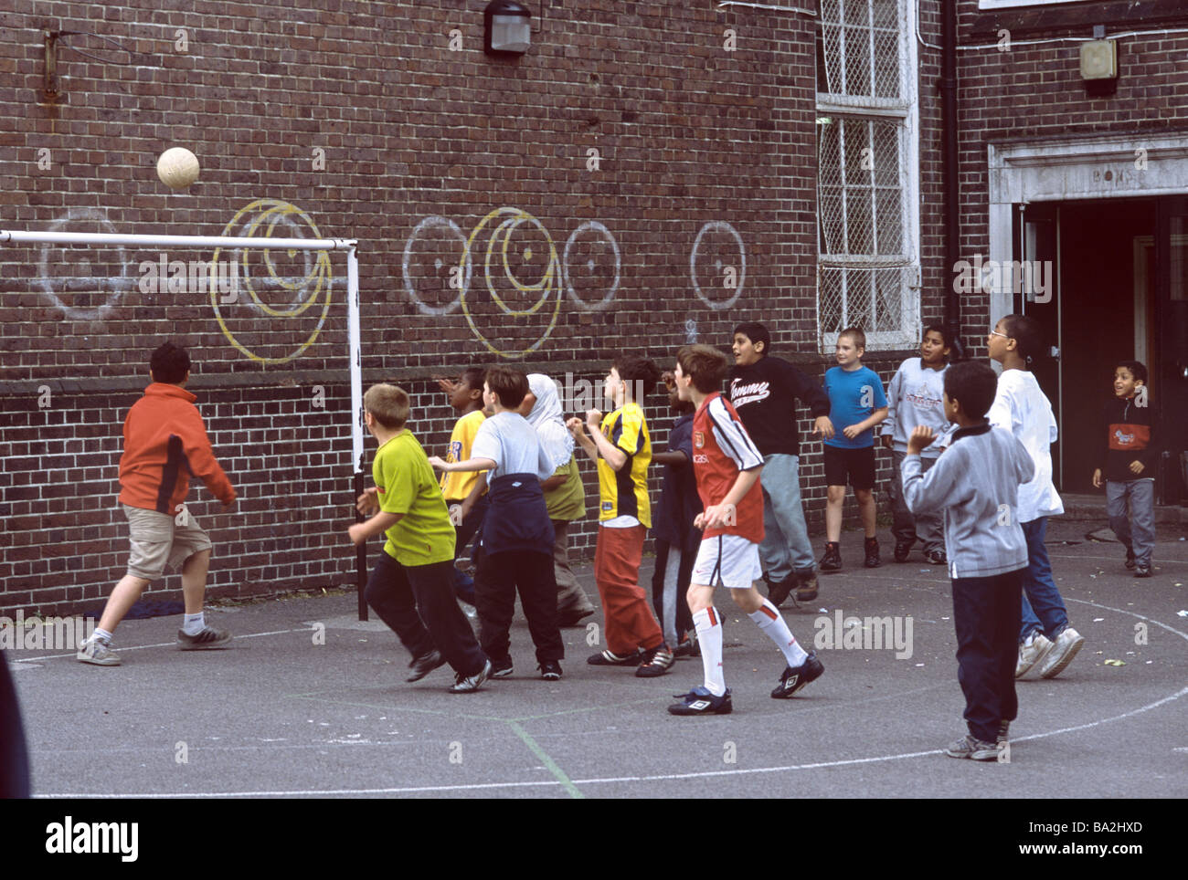 Primary school playground with children playing soccer on the pavement ...