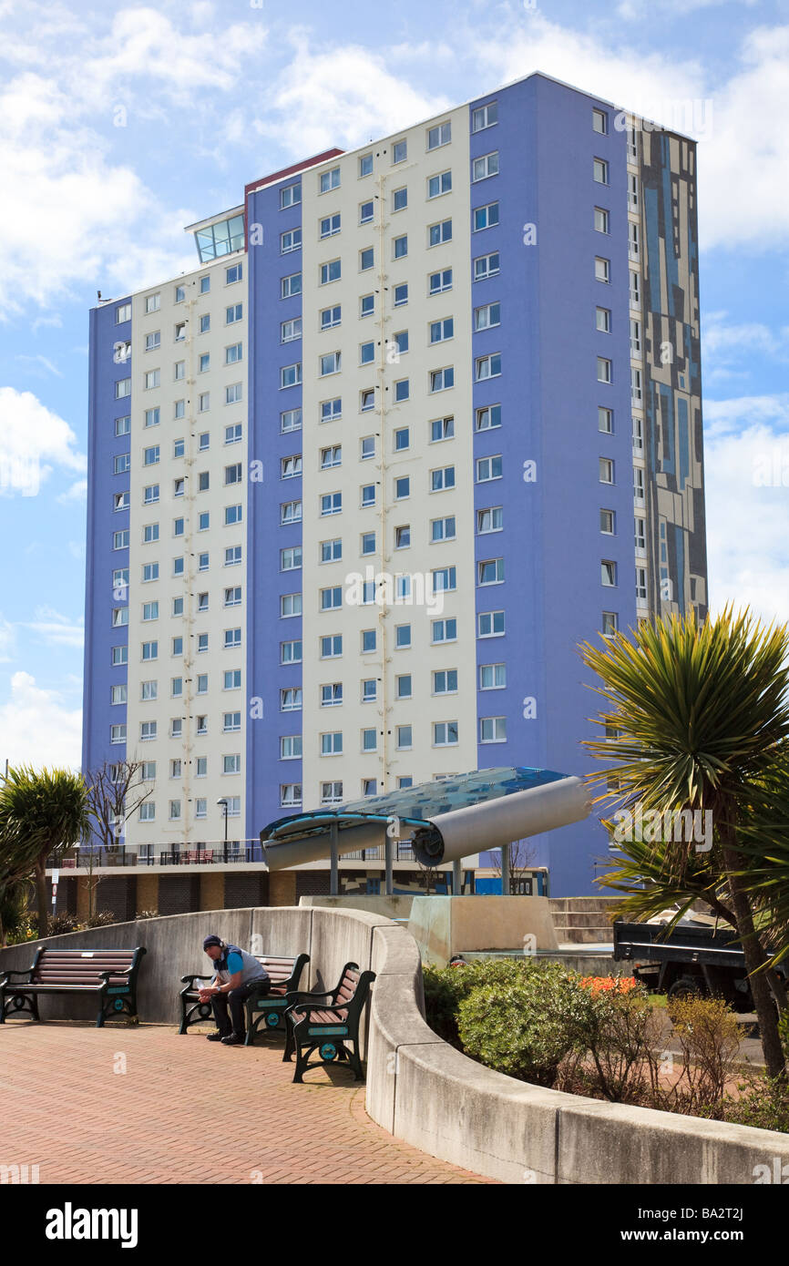 A man sits on benches on Gosport Seafront A tower block behind him ...