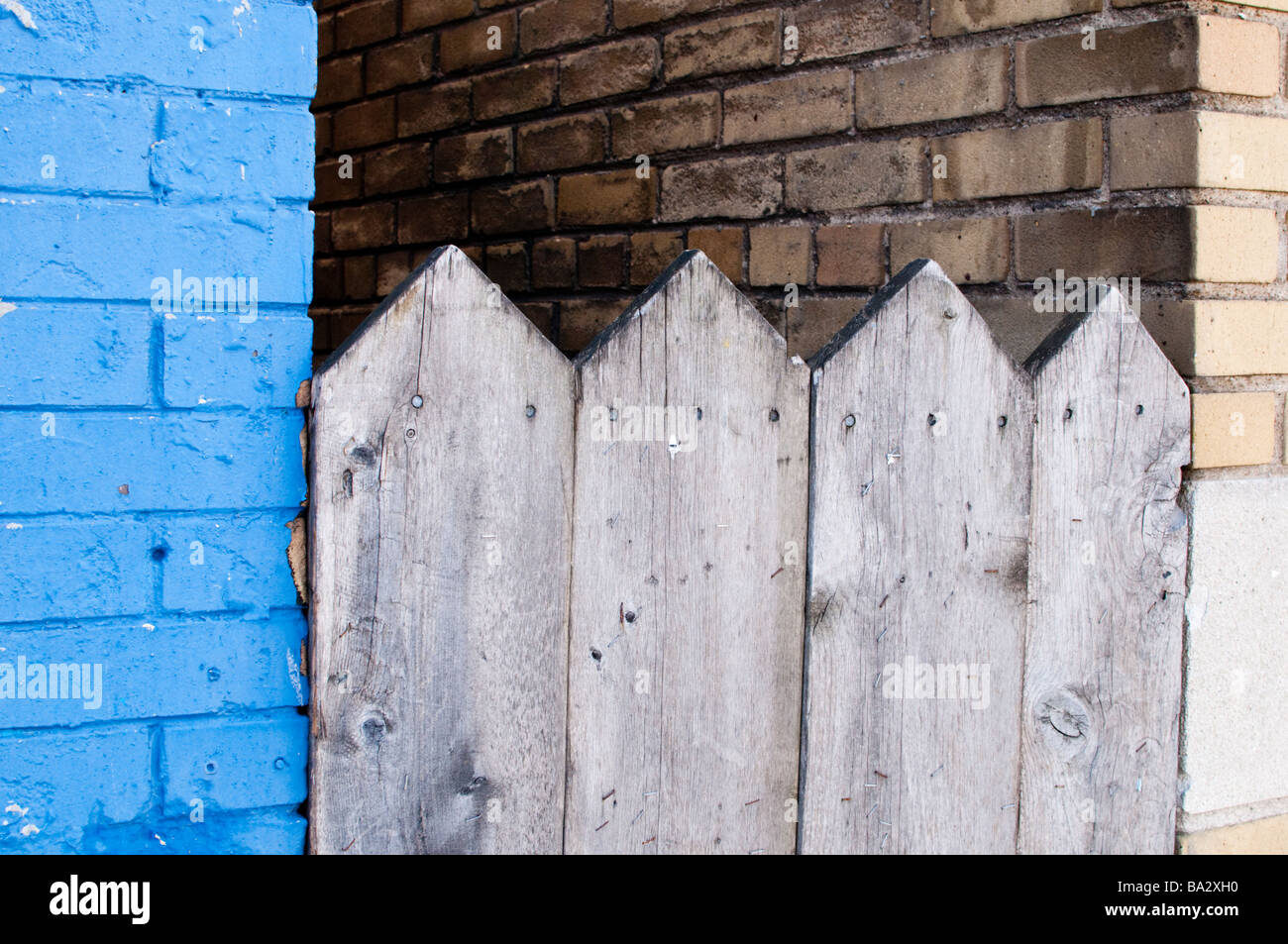 A wooden fence between brick walls Stock Photo - Alamy