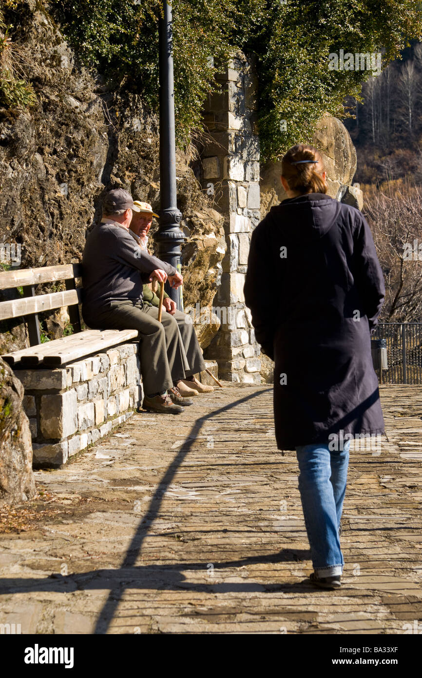 A girl passing by two senior men sitting on a bench in Aragonian ...