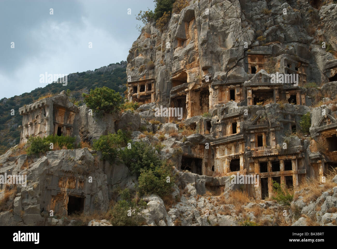 Tombs carved into the side of a cliff overlooking the ruins of the ...