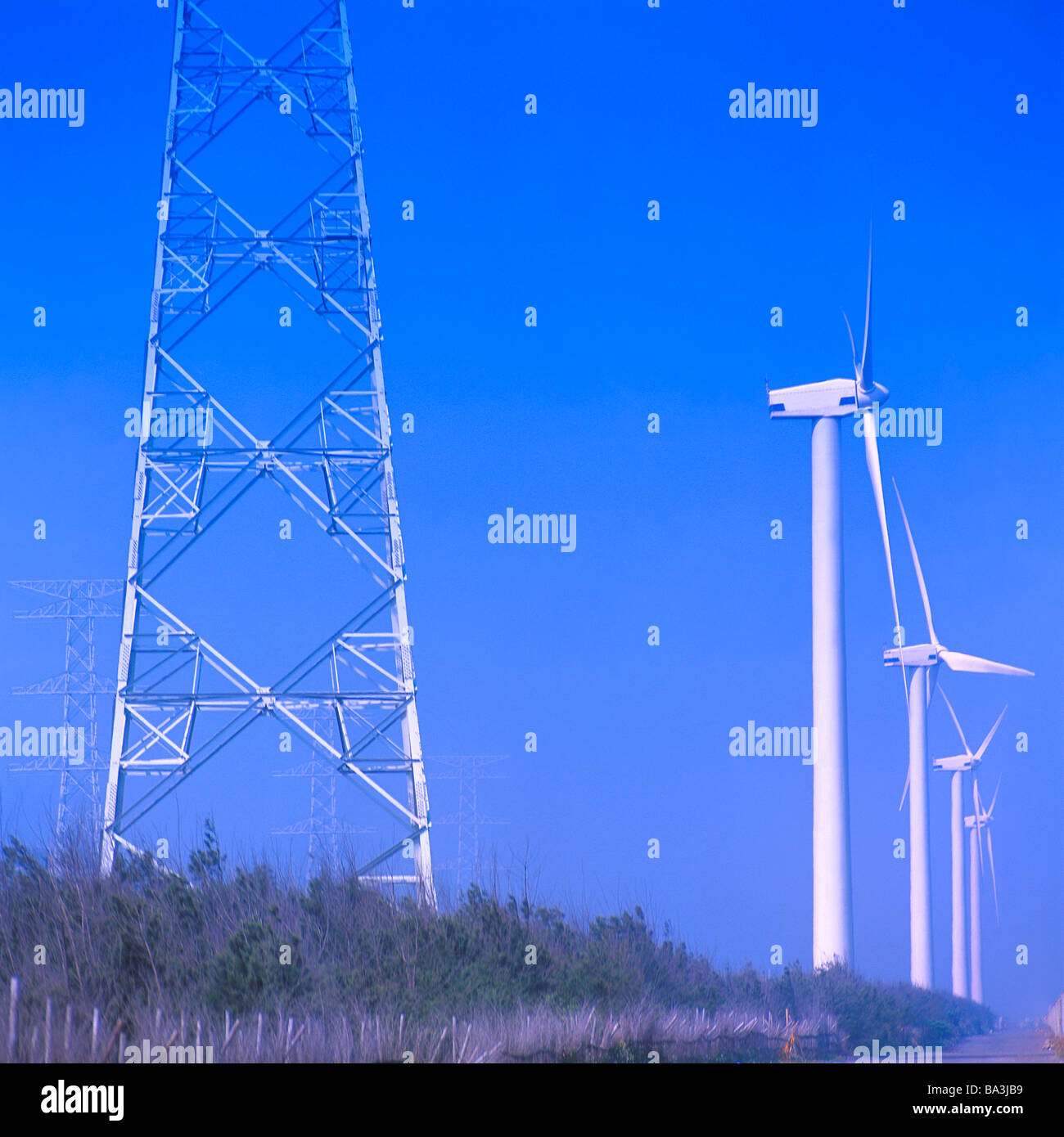 Wind turbines by electricity pylon Stock Photo - Alamy