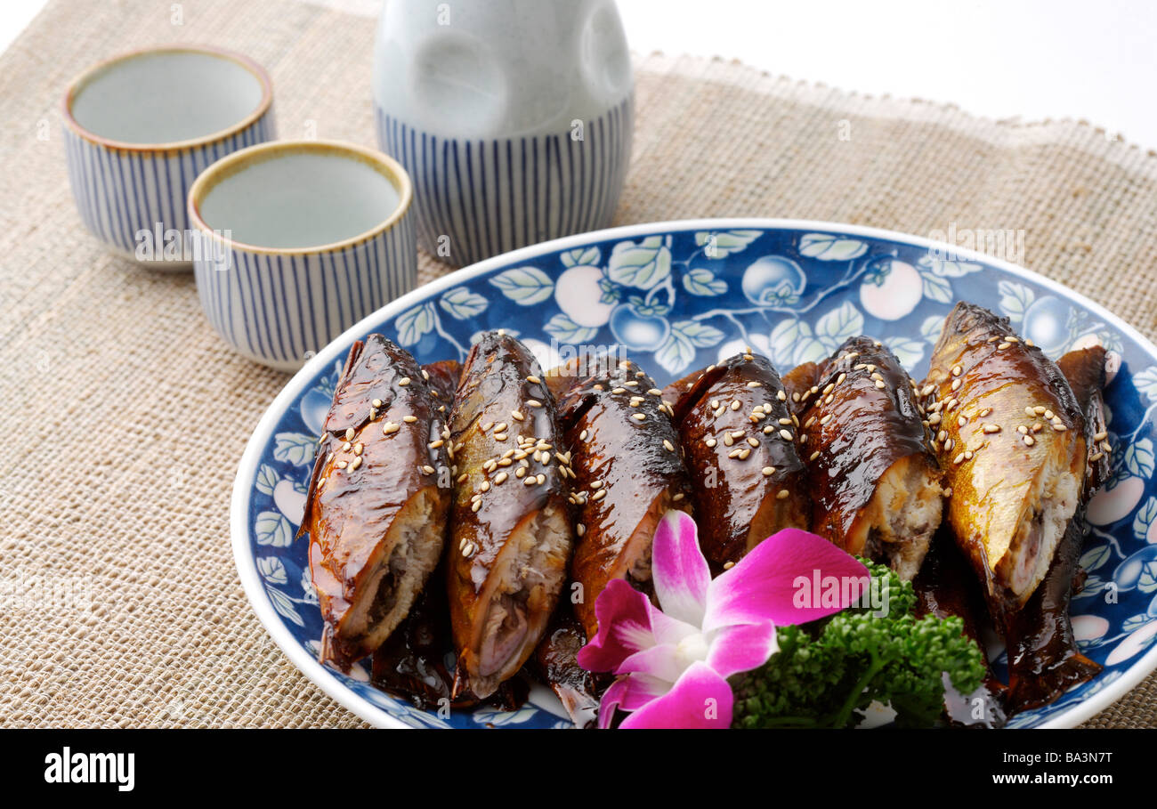 Roasted fish on plate with sesame on top saki in the background Stock ...