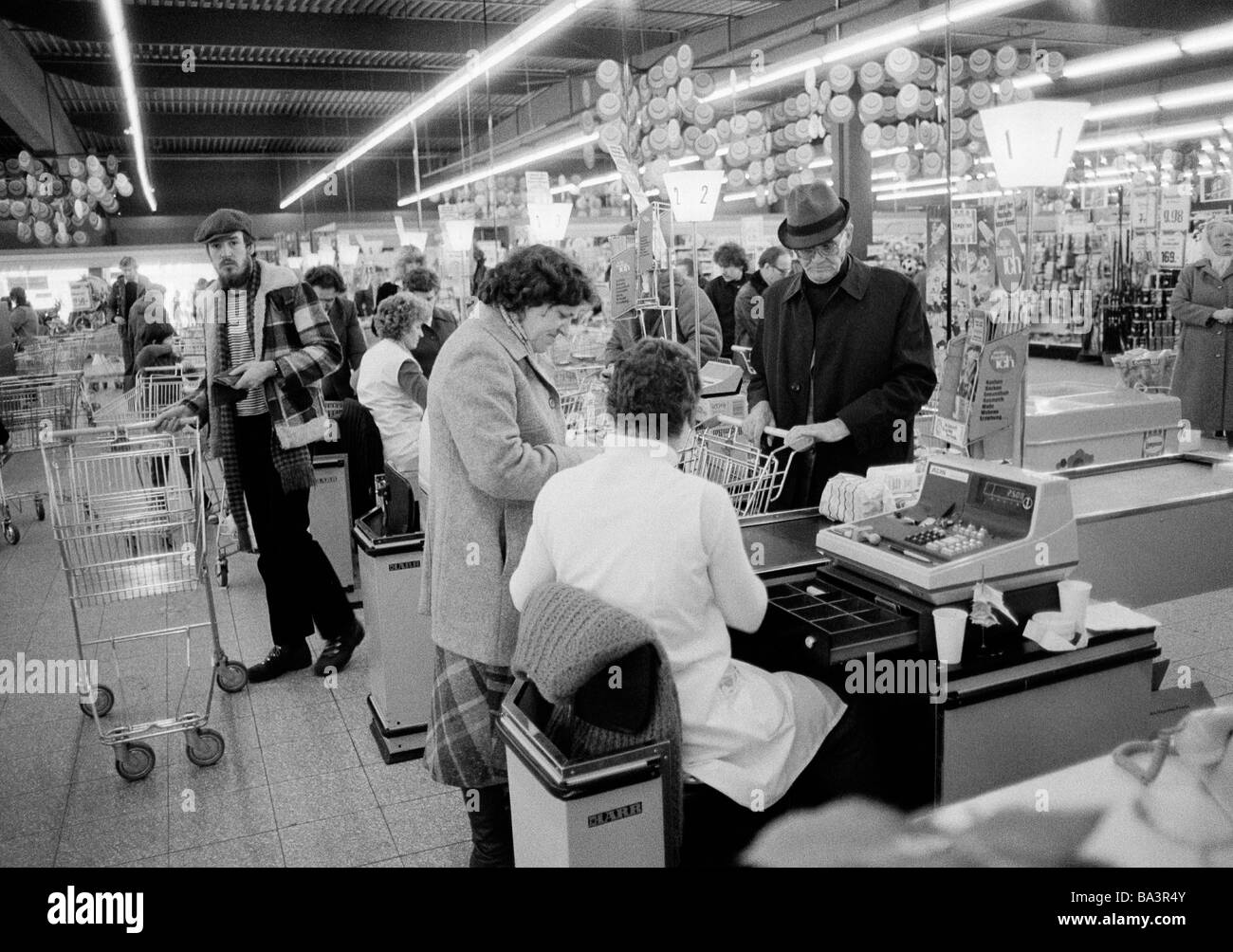 Eighties, black and white photo, economy, cashier and customers at a ...