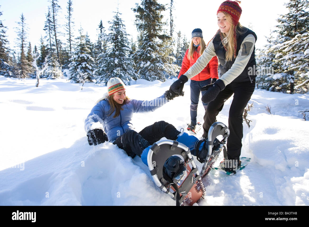 Two young women help up a third after she fell during their snowshoe ...