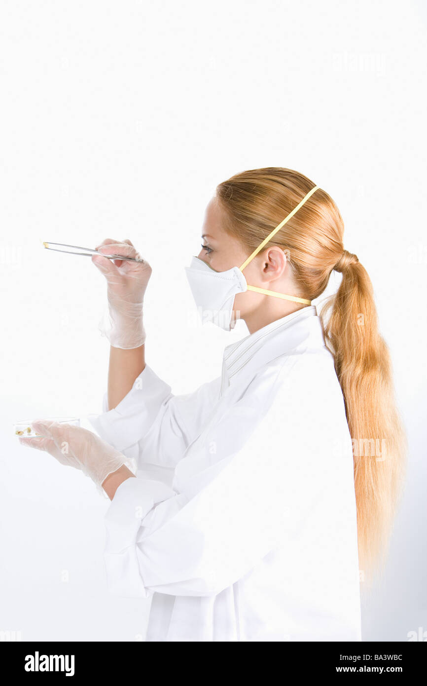 One woman in lab coat examining seed side view Stock Photo - Alamy